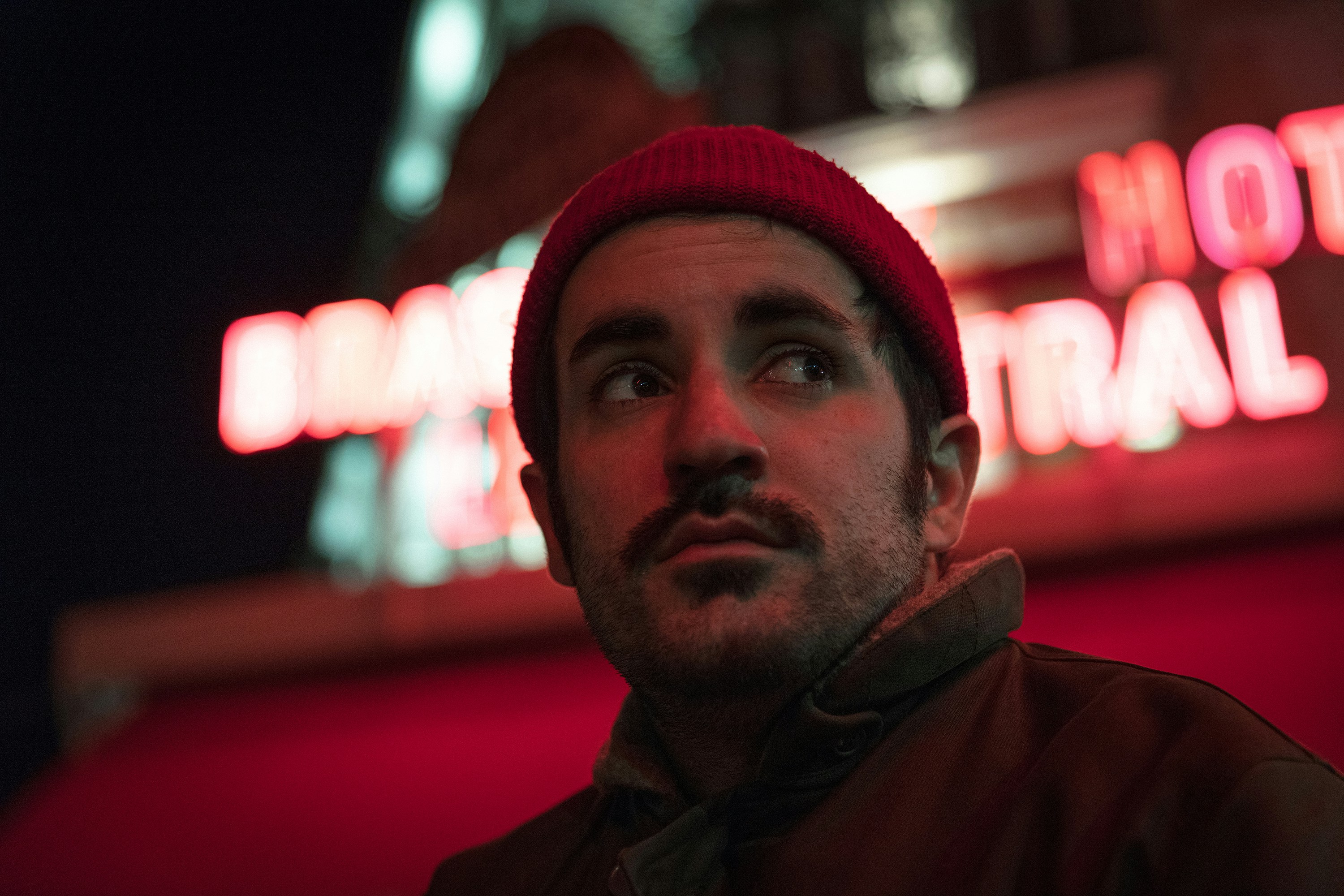 Crimson Beanie, Neon Backdrop: A Quiet Night Portrait