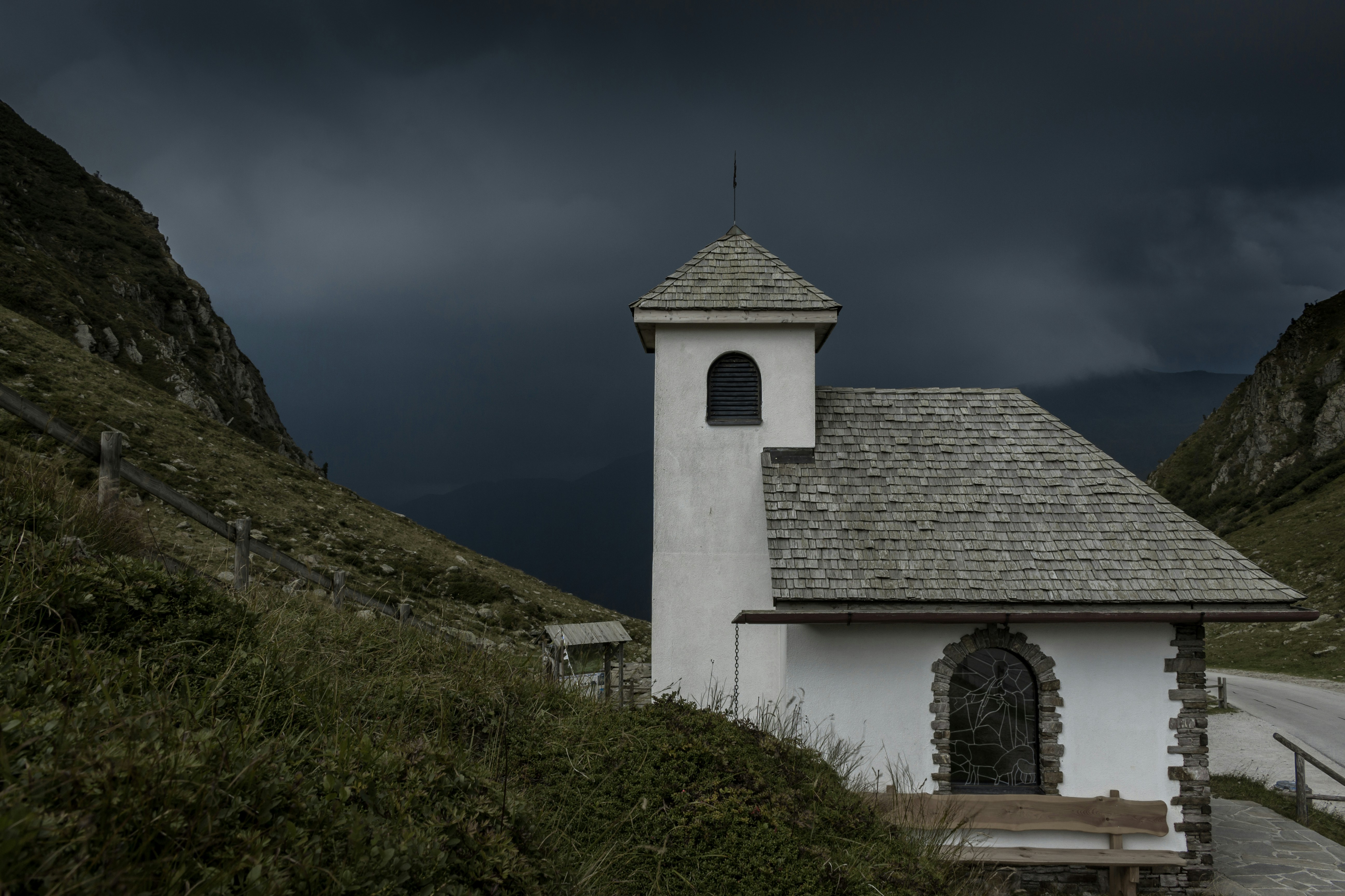 White Chapel on a Mountain Pass Beneath a Looming Storm