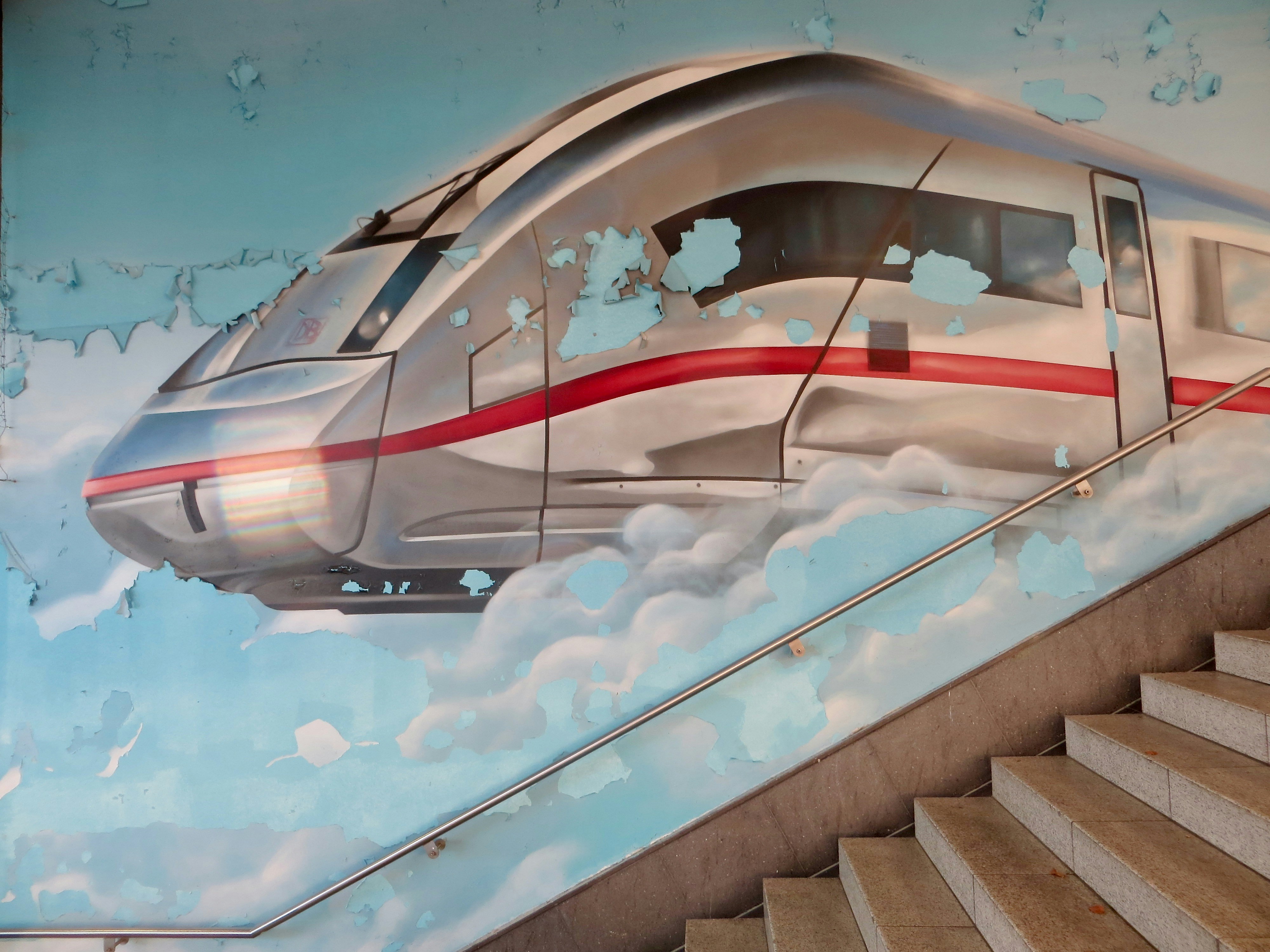 Vibrant mural painting of a sleek high-speed train slicing through clouds along a stairwell wall.