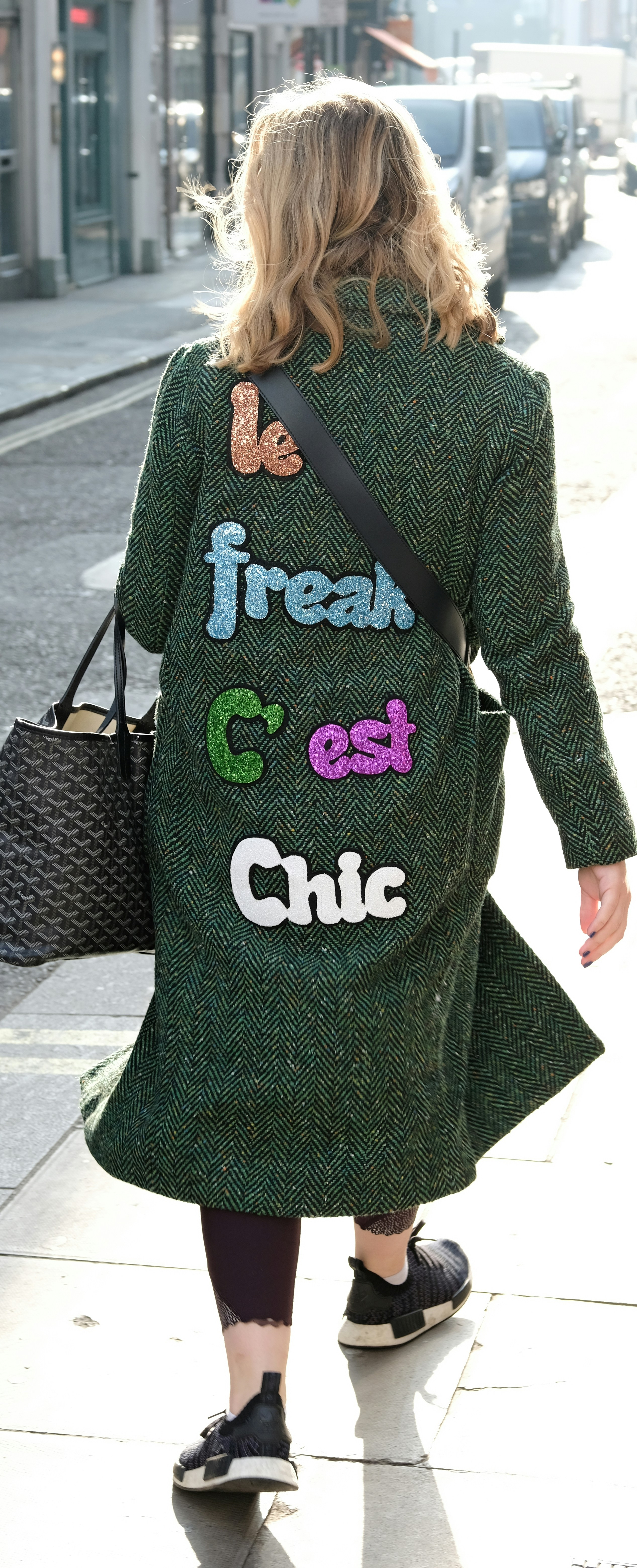 Patchwork Promenade: Colorful Letters on a Green Coat Walk the City Street