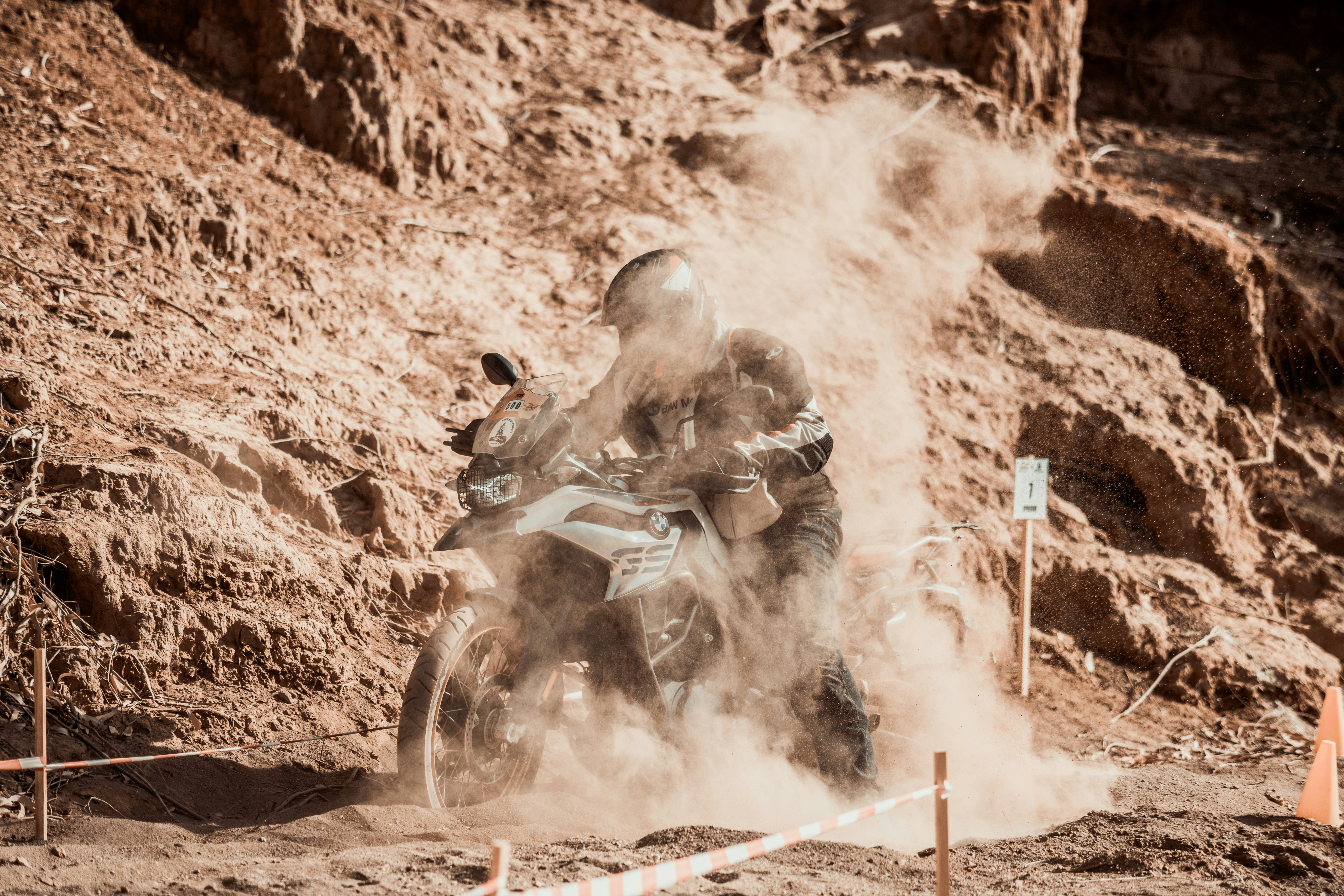 Dustbound Descent: A Dirt-Bike Rider Cuts Through Red Dust on a Rugged Desert Track