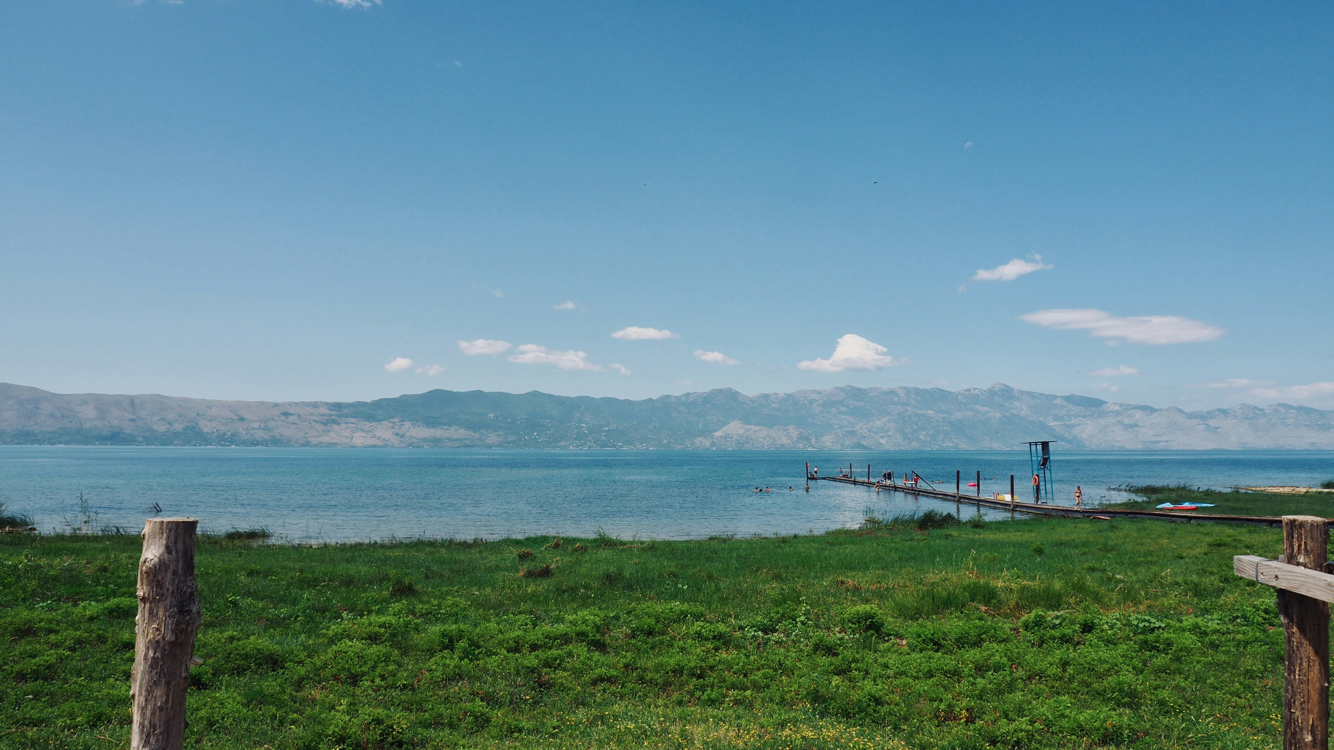 Serene lakeside panorama with a wooden jetty and distant mountains