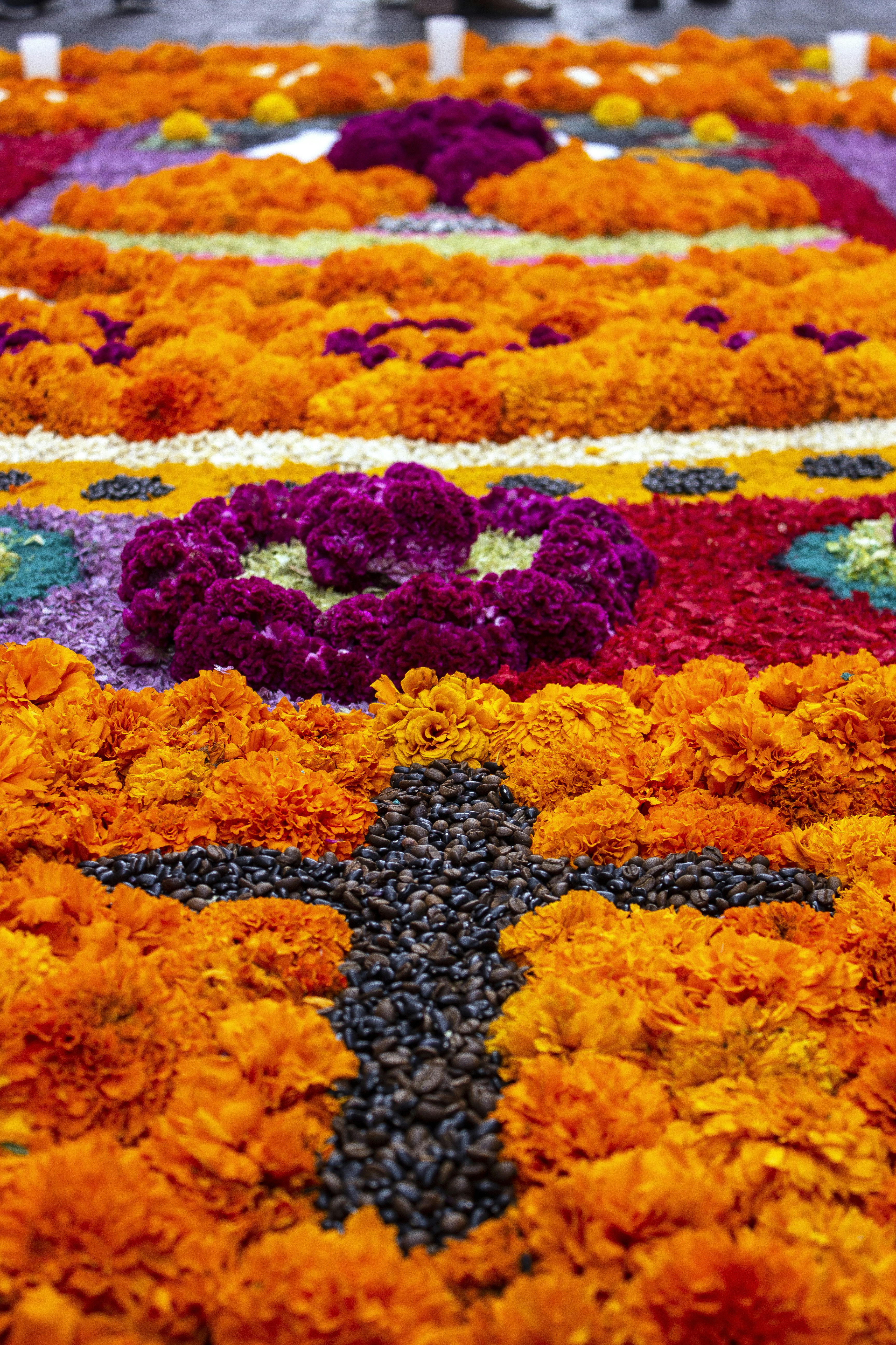 Colorful marigold and petal arrangement with intricate patterns in a public space.