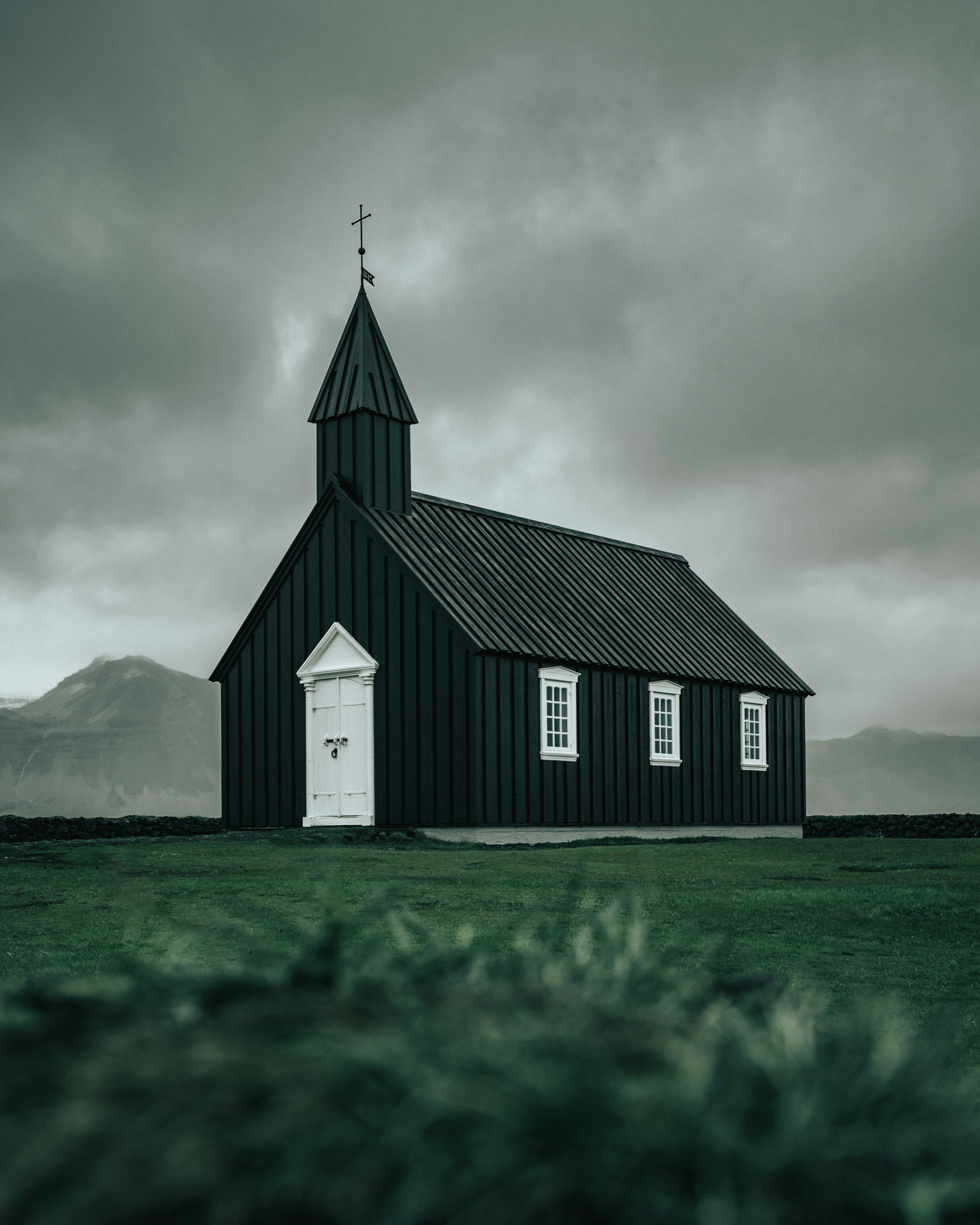 White and black wooden church on green field viewing mountain during ...