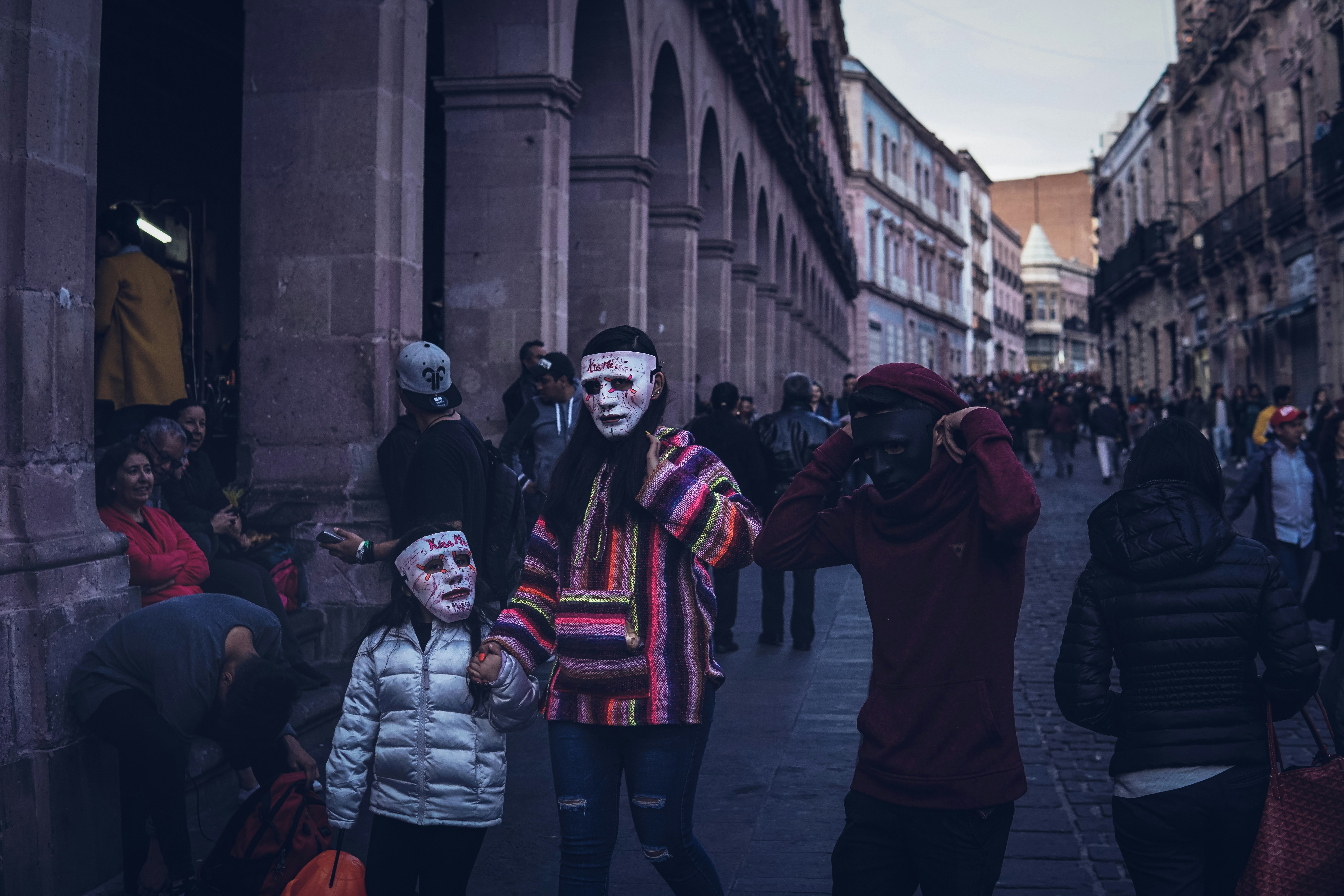 People wearing masks walk through a crowded street during a festival in Zacatecas.