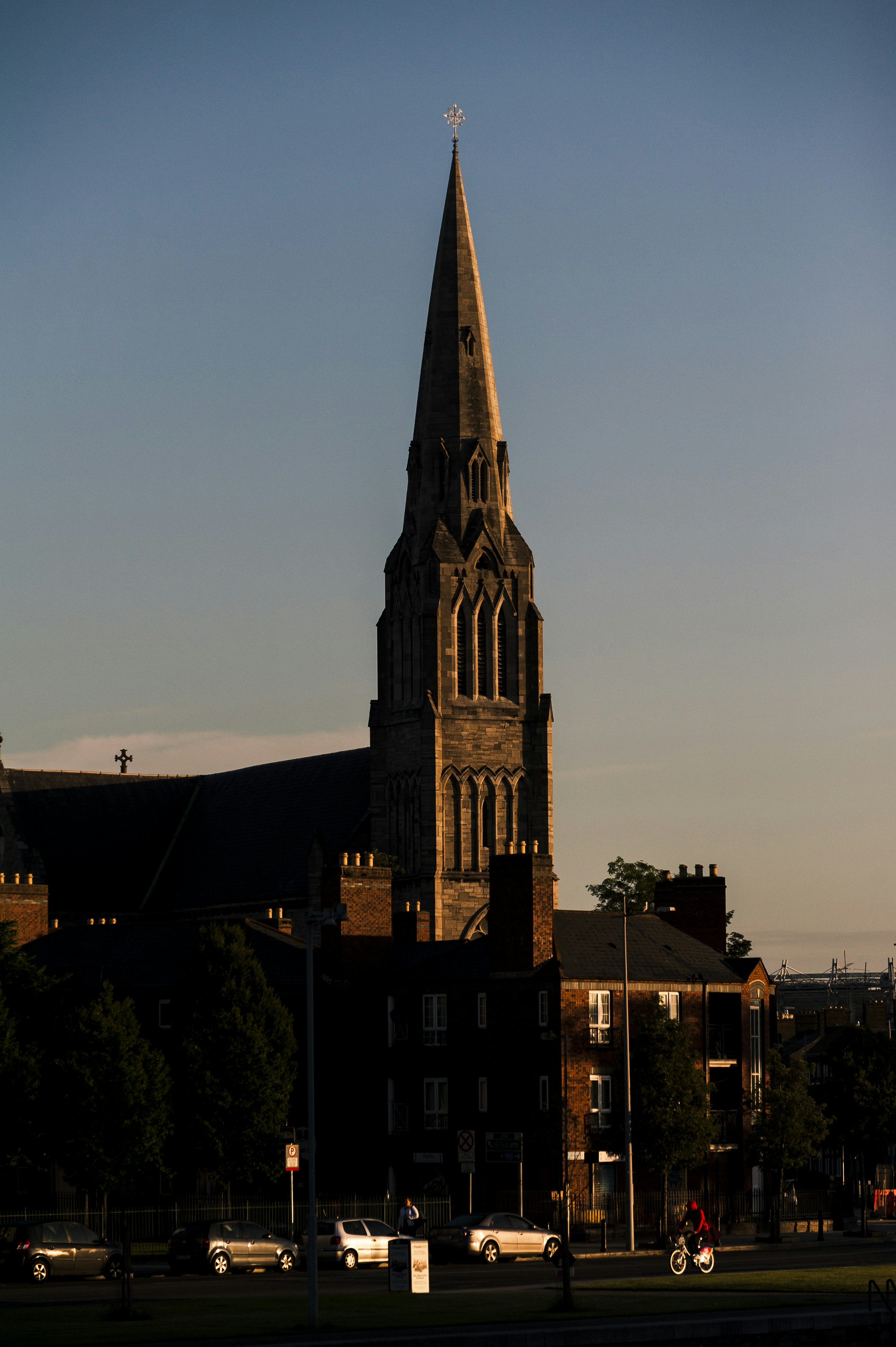 Tall church steeple silhouetted against a warm sunset sky, highlighting intricate architectural details.