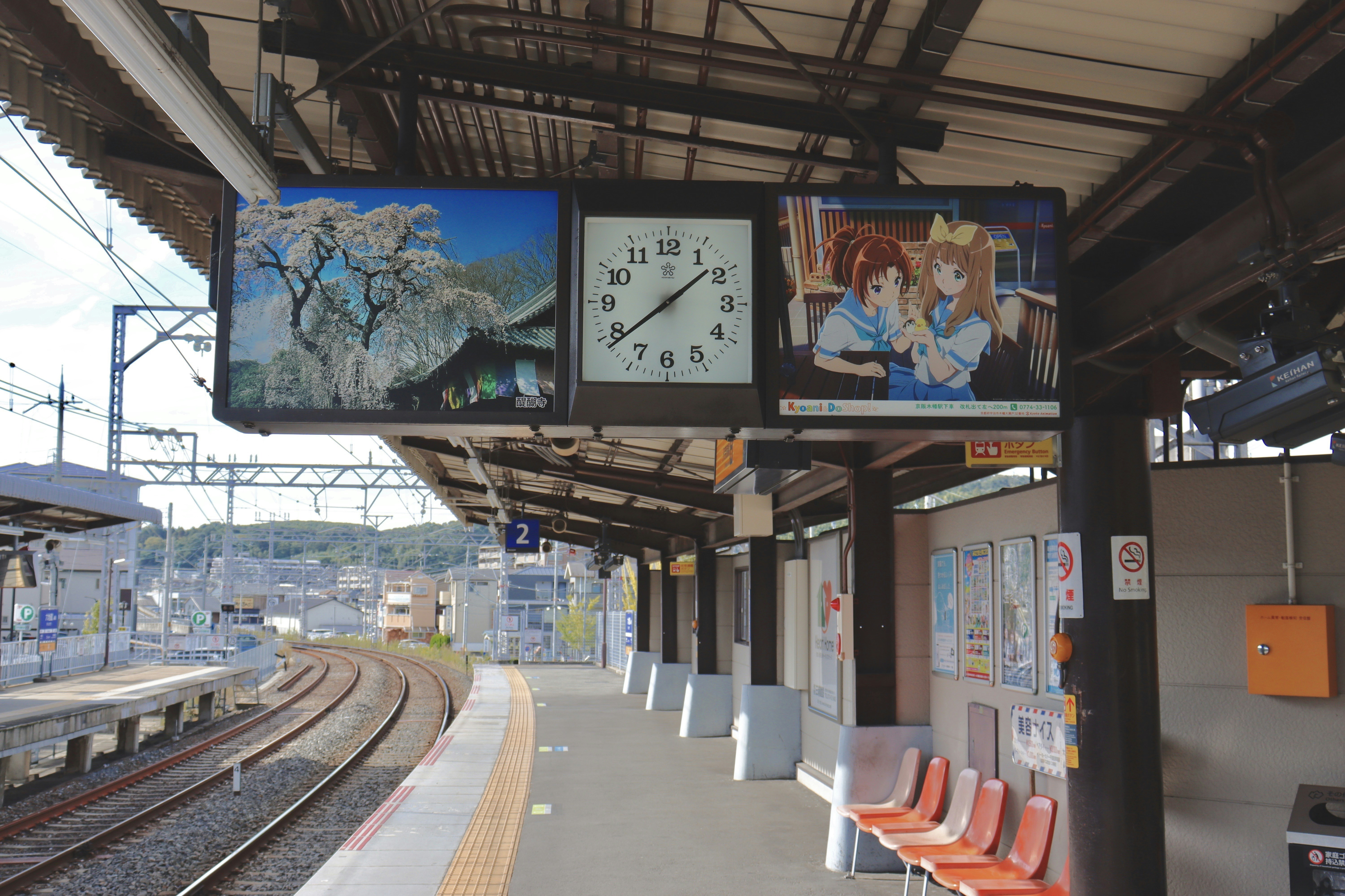 Train station platform with wall clock and art panels under a covered roof.