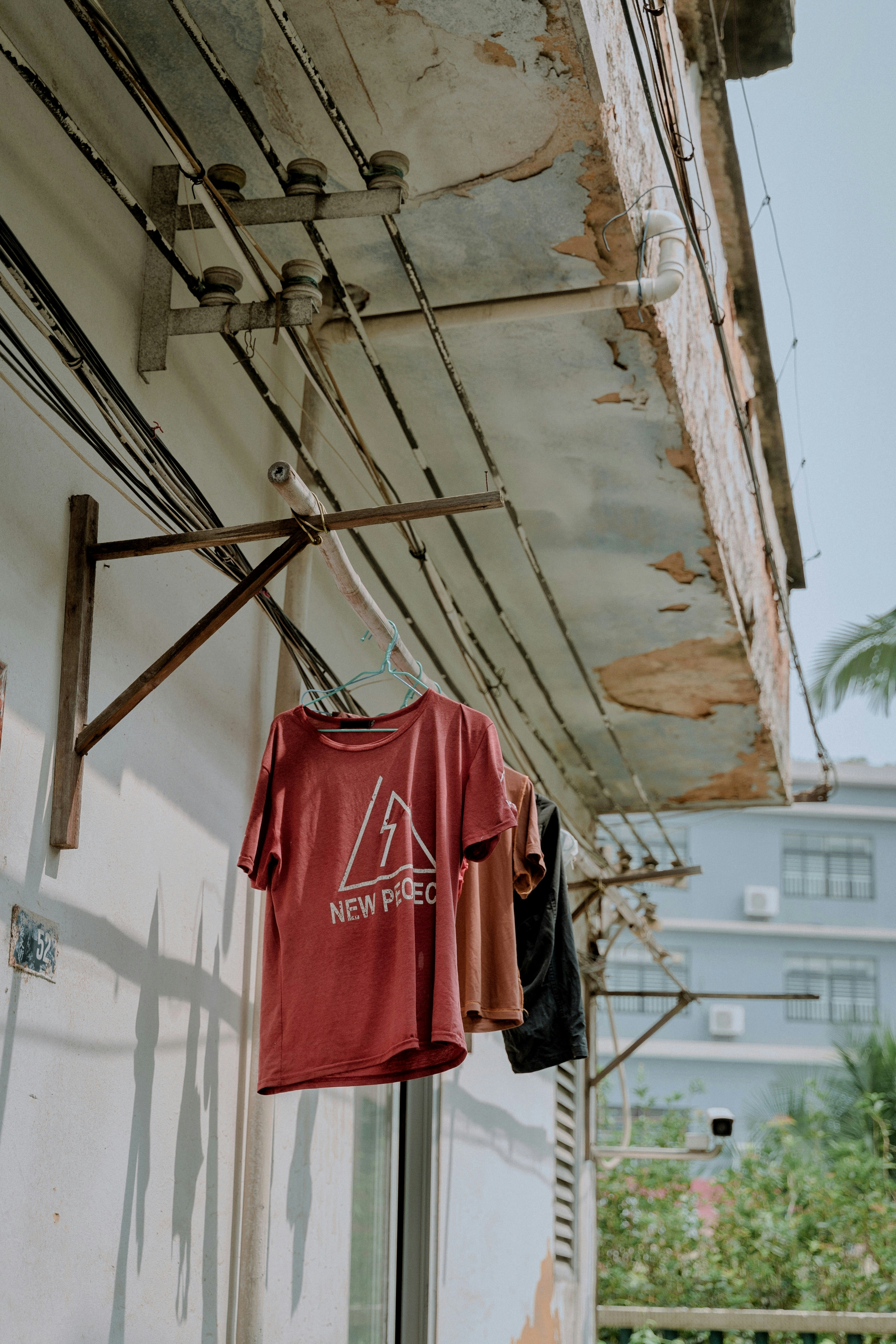 Red Tee on a Weathered Balcony: Quiet urban laundry framed by peeling plaster