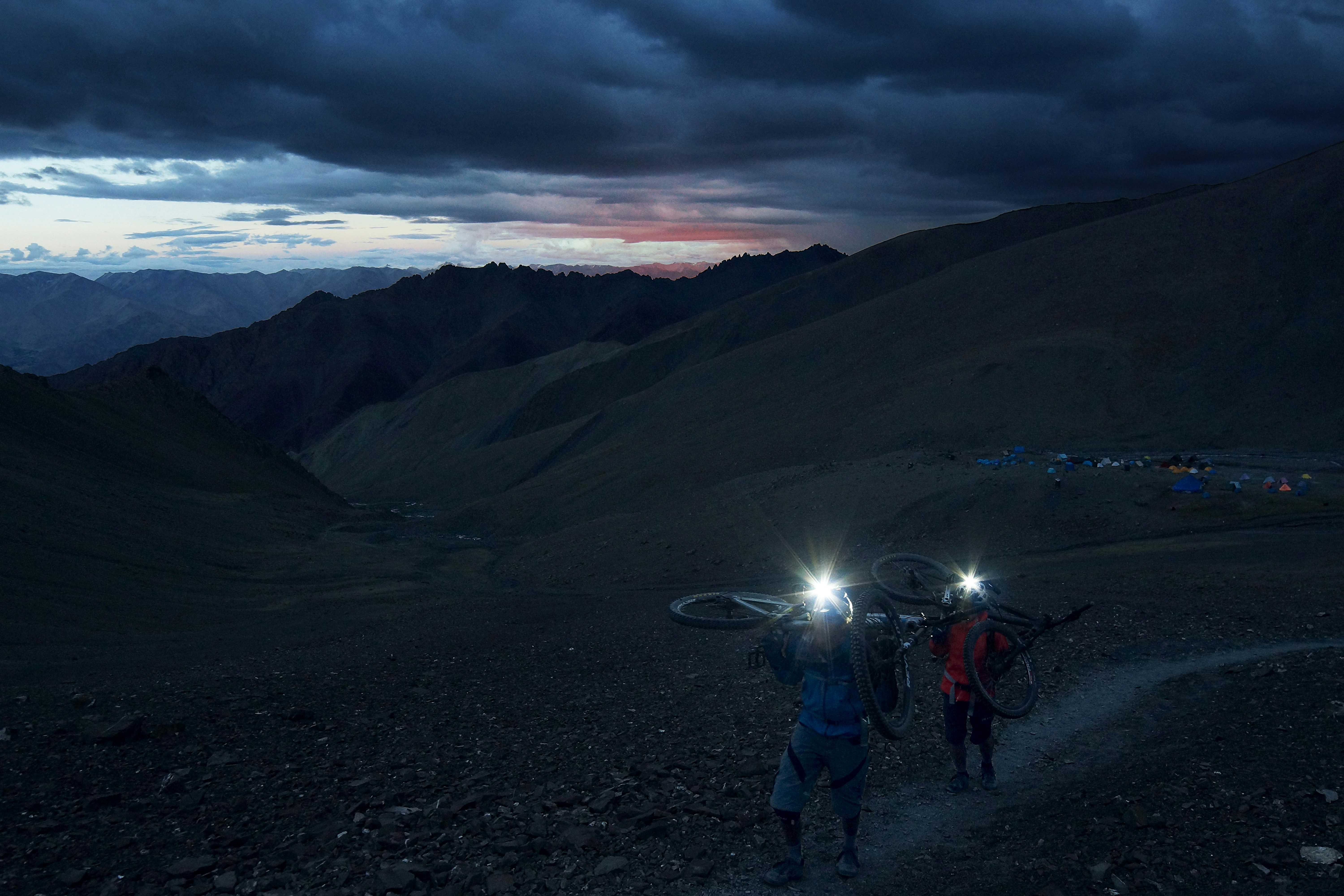 Night Descent: Cyclists Reaching a Mountain Camp under a Stormy Sky