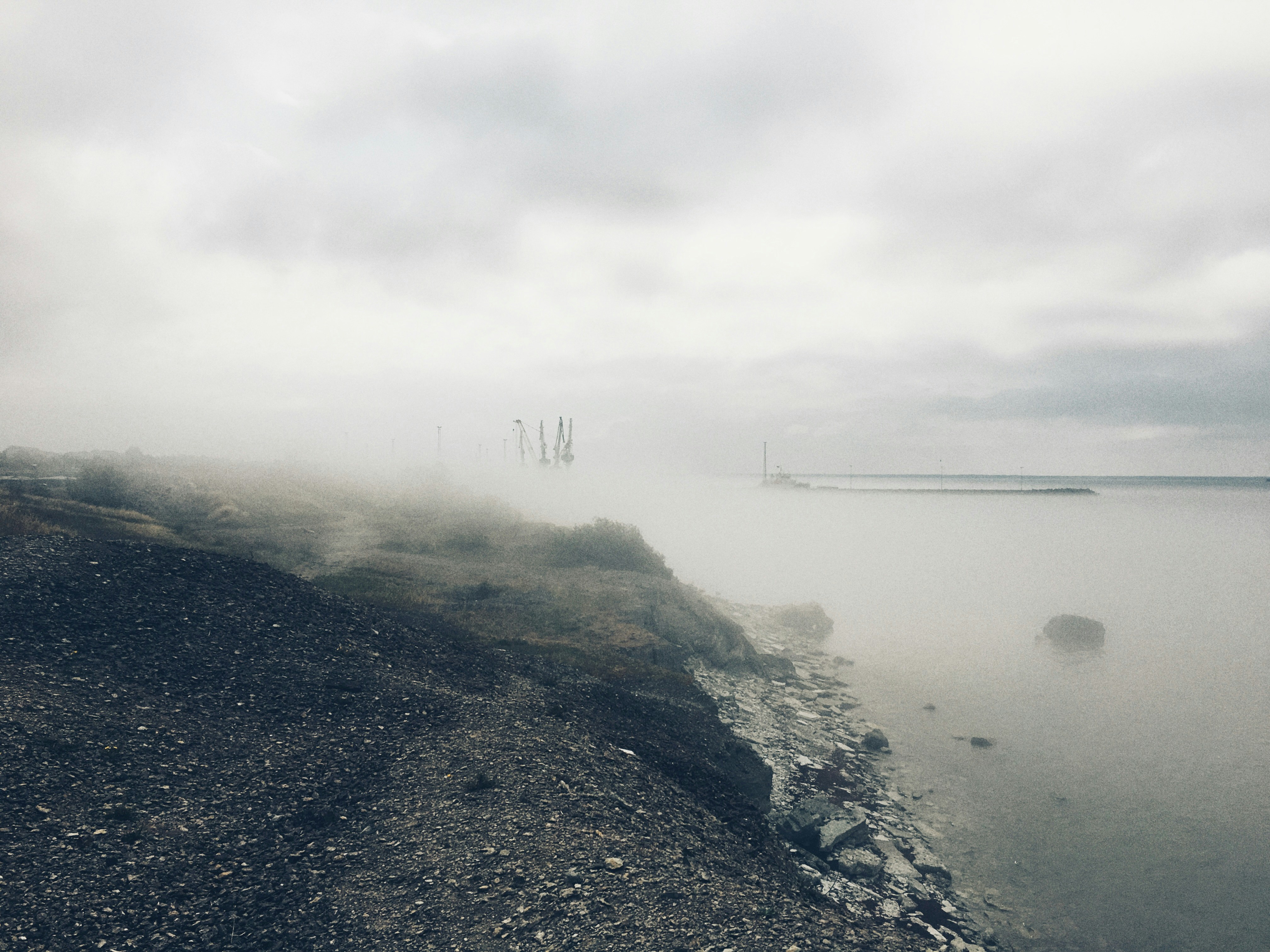 mist covering hill near body of water