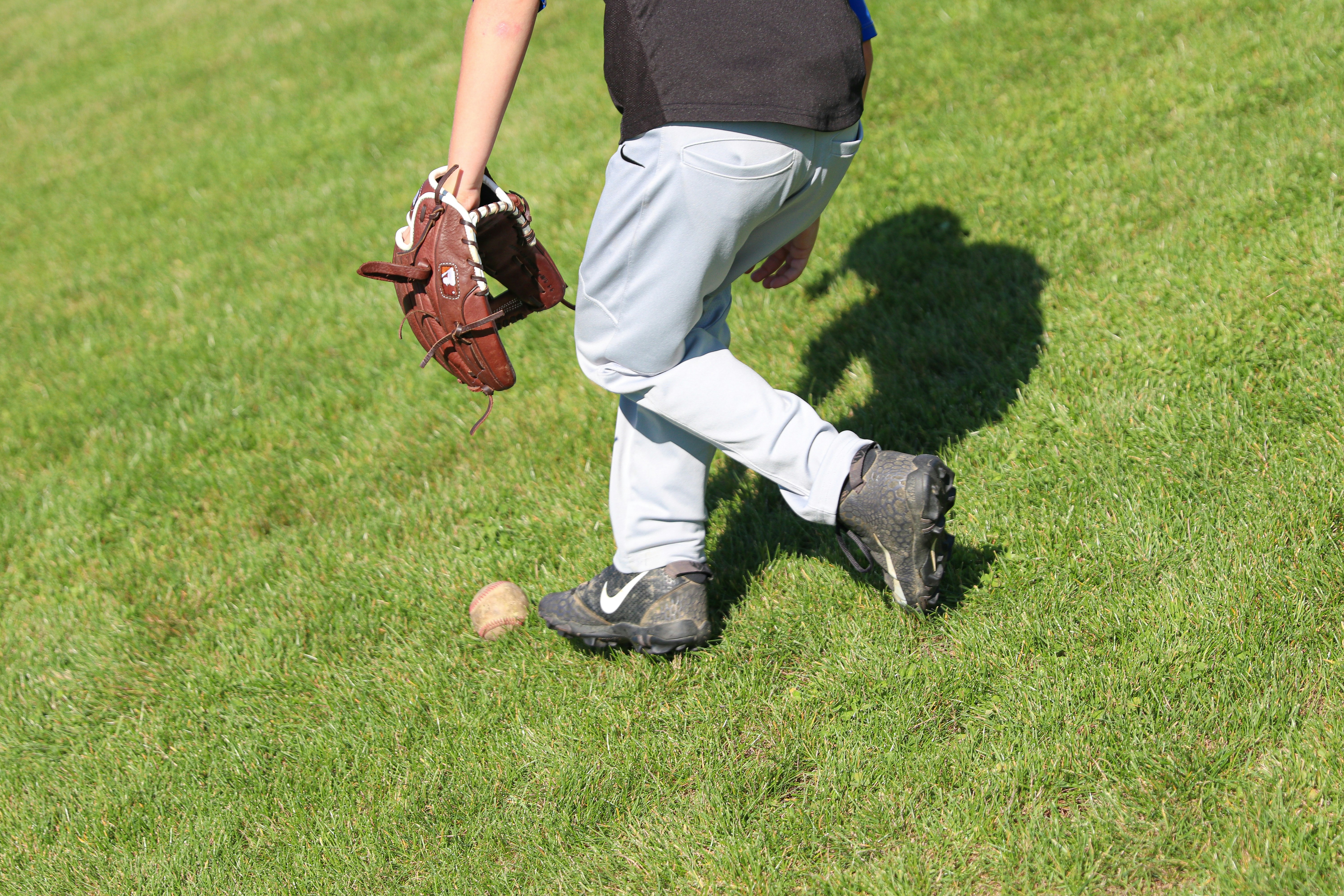 Man standing on grass field picking up baseball photo – Free People ...