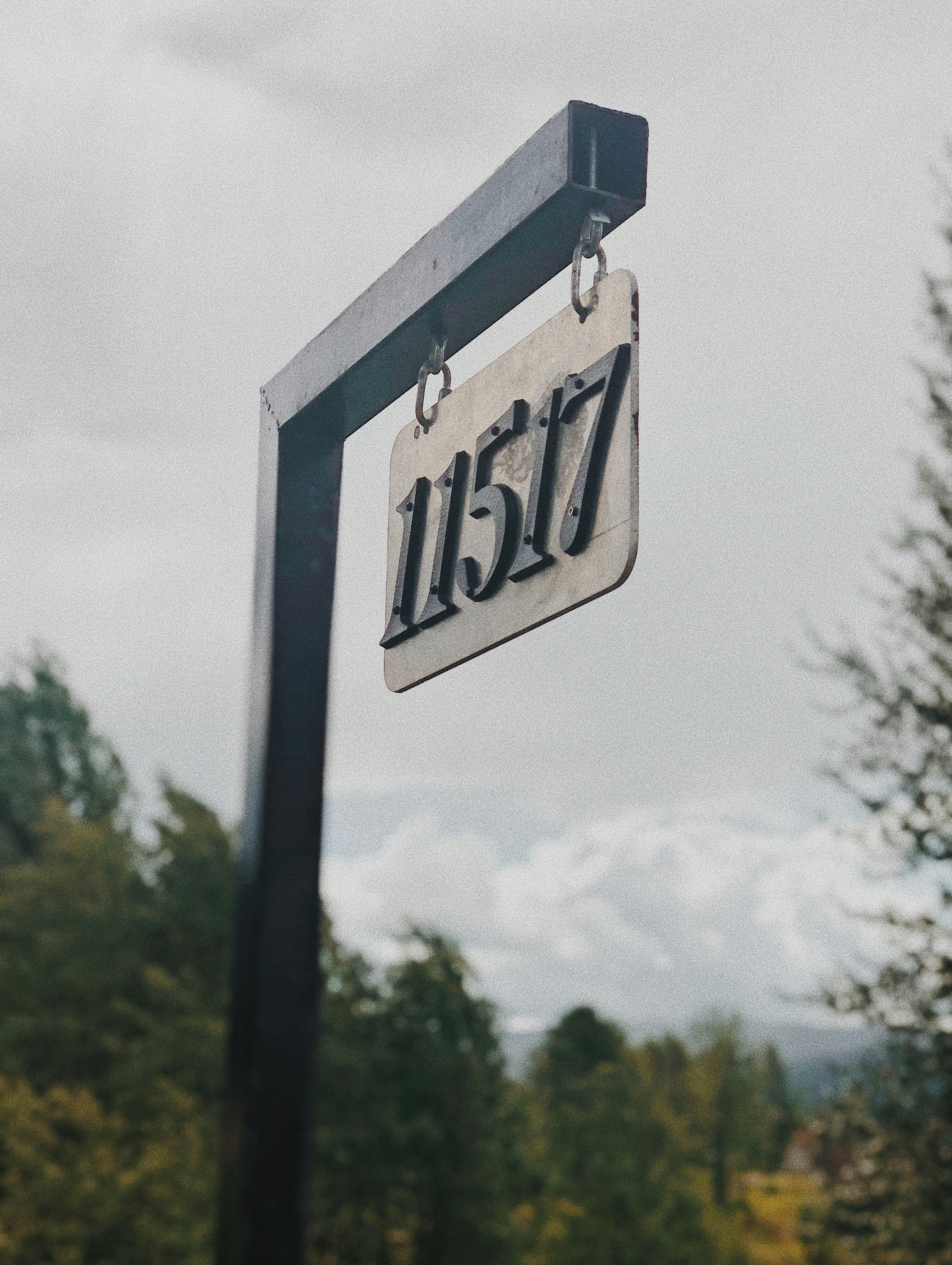 Weathered 1157 Sign Hoisted Against a Quiet Autumn Landscape