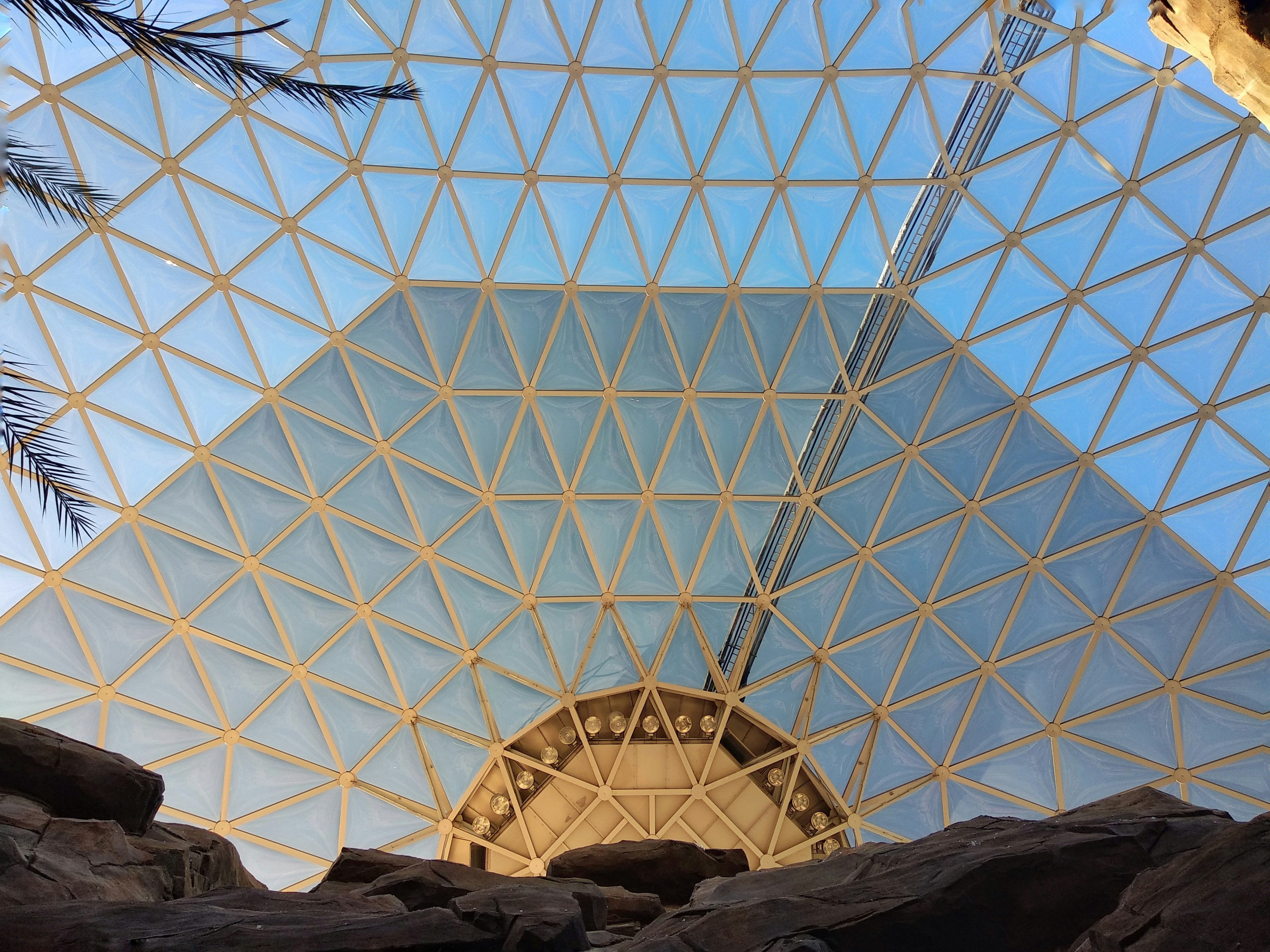 Glass dome structure with triangular patterns against a clear sky.