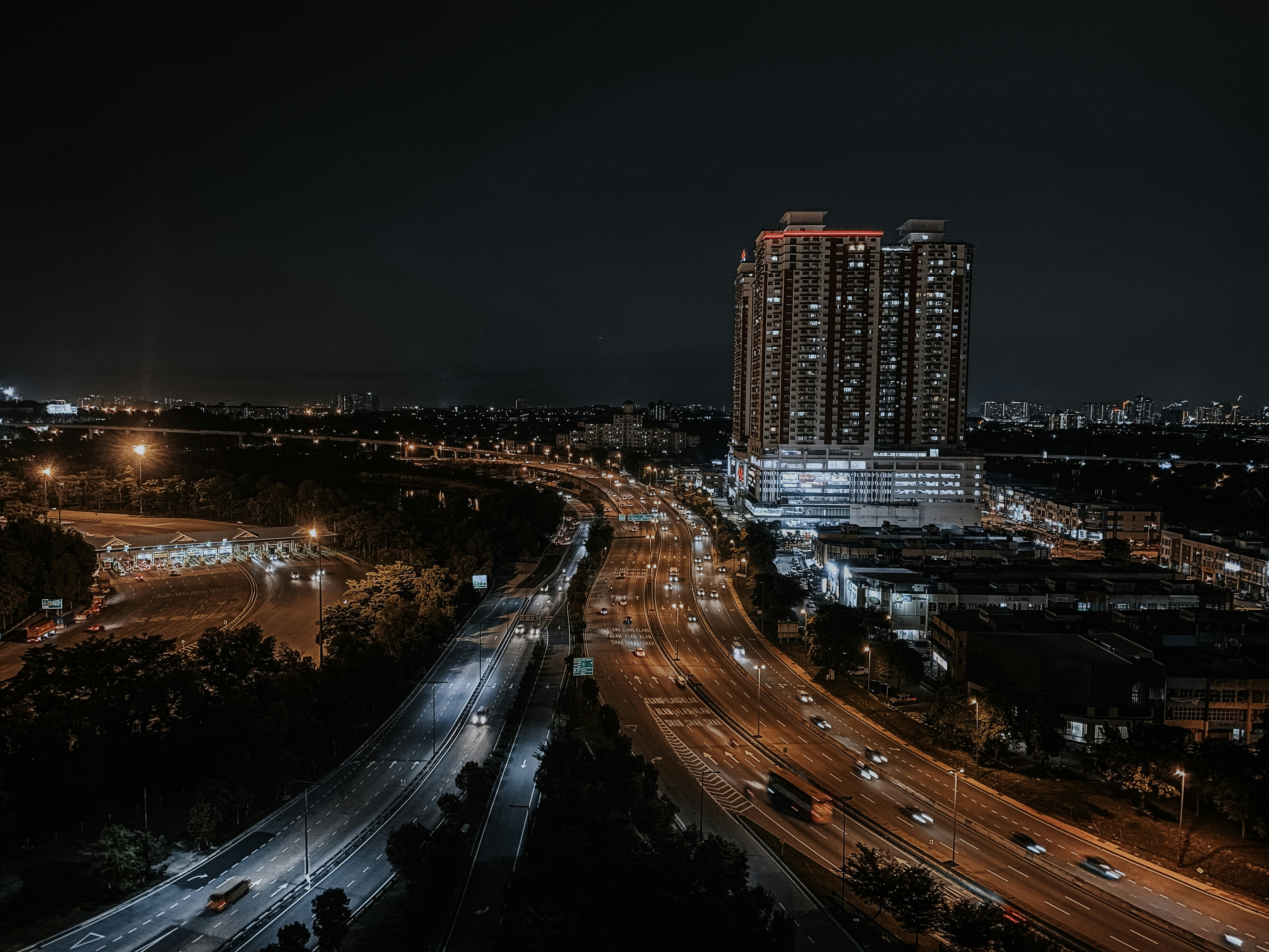 Illuminated highways intertwine beneath towering buildings in a vibrant cityscape at night.