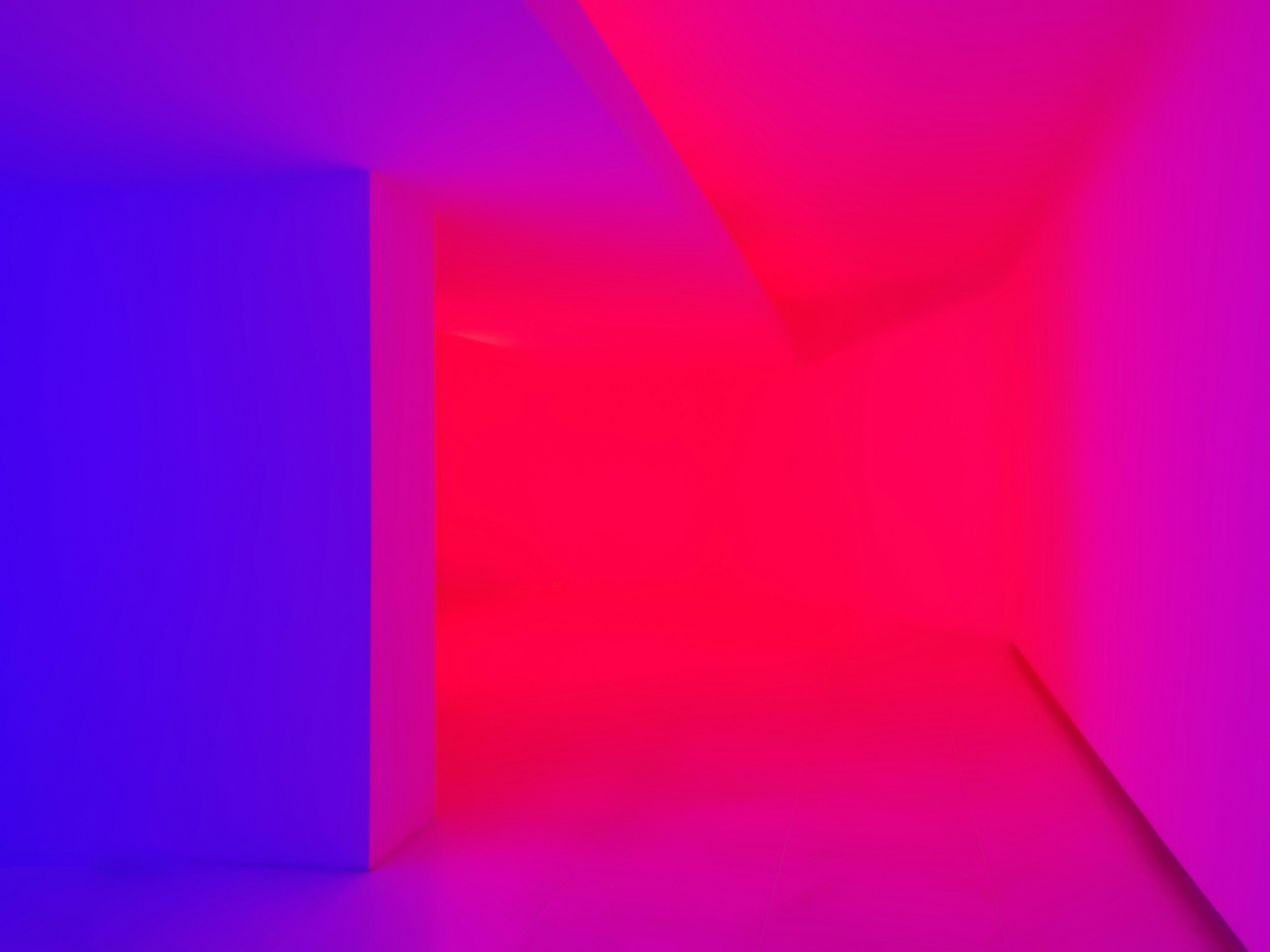 Abstract neon-lit corridor bathed in magenta and blue hues, with geometric walls converging toward a red-lit vanishing point.