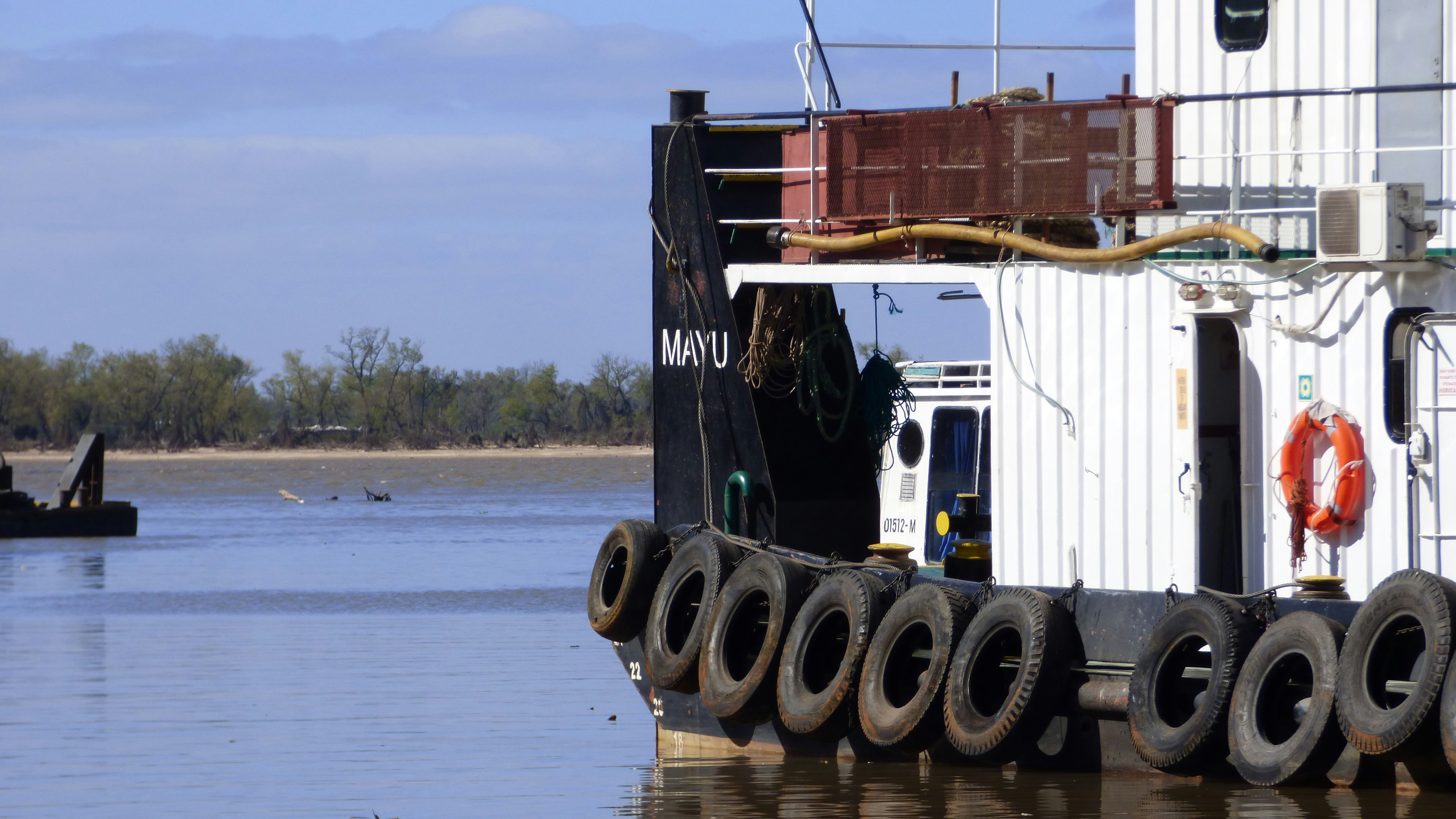 Harborfront Ferry Pier Adrift: Tire-Walled Barge at Distant Shore