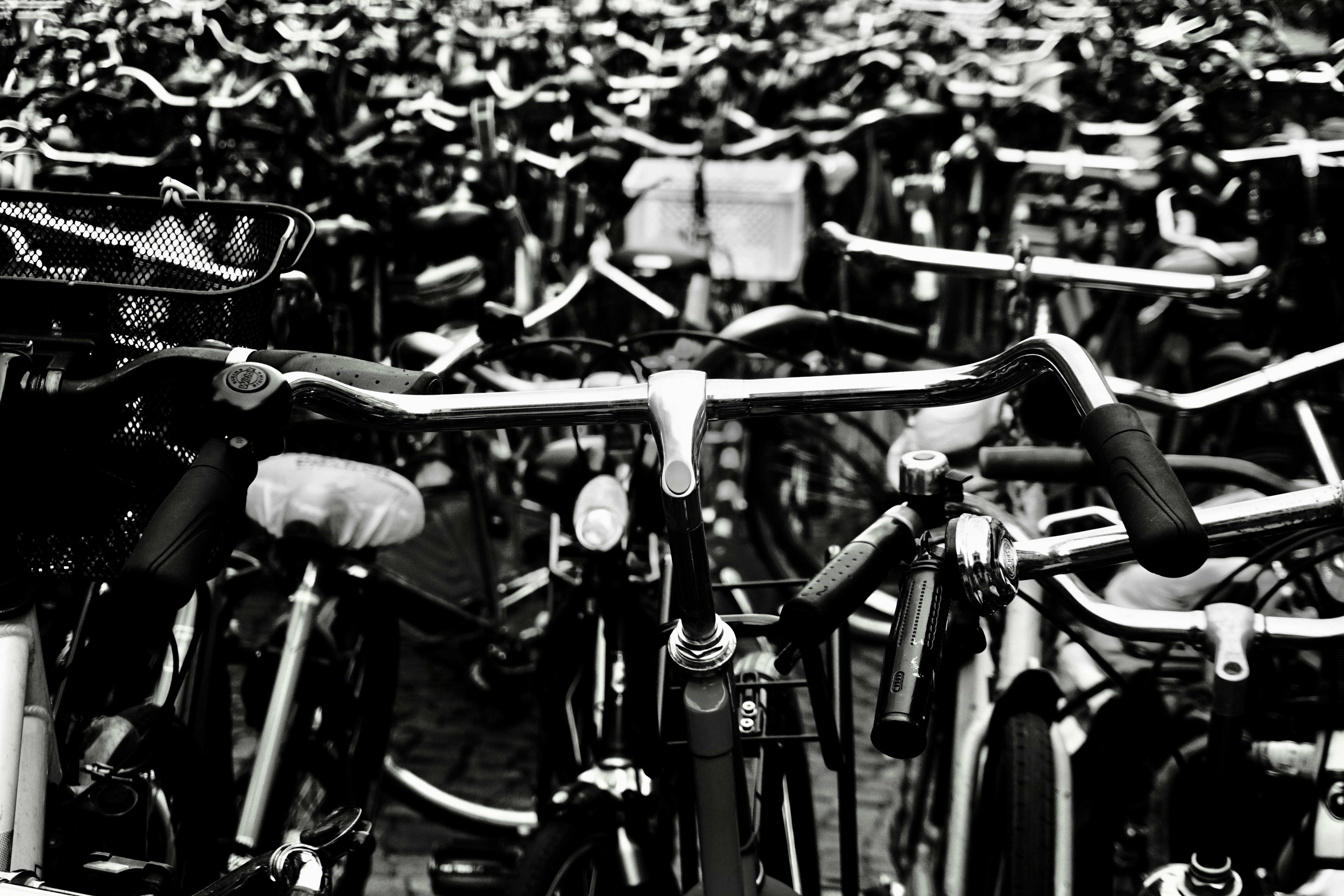 Grayscale photograph of a dense cluster of bicycle handlebars creating a maze-like pattern.