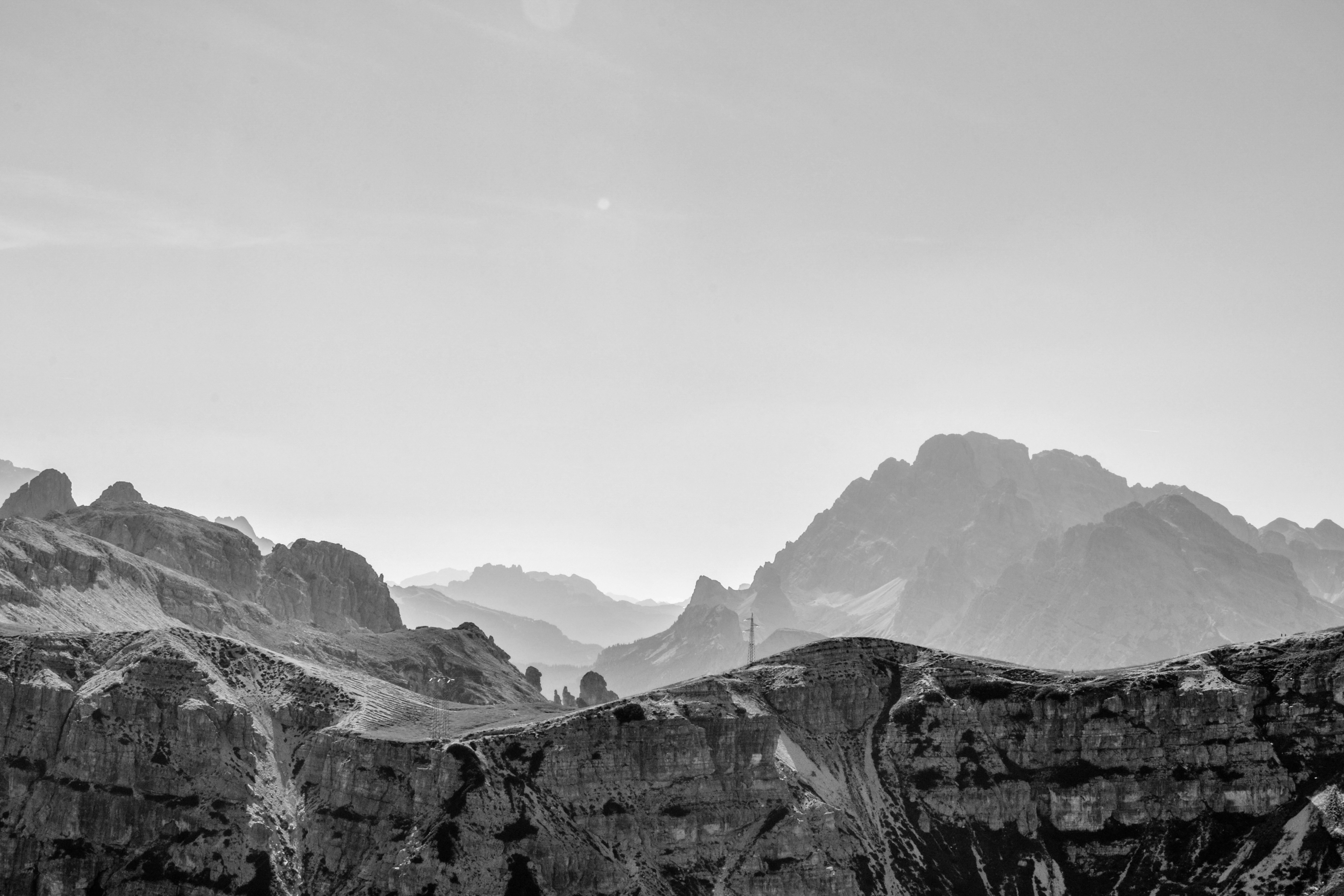 Monochrome landscape showcasing rugged mountain silhouettes under a soft sky, highlighting the interplay of light and shadow.