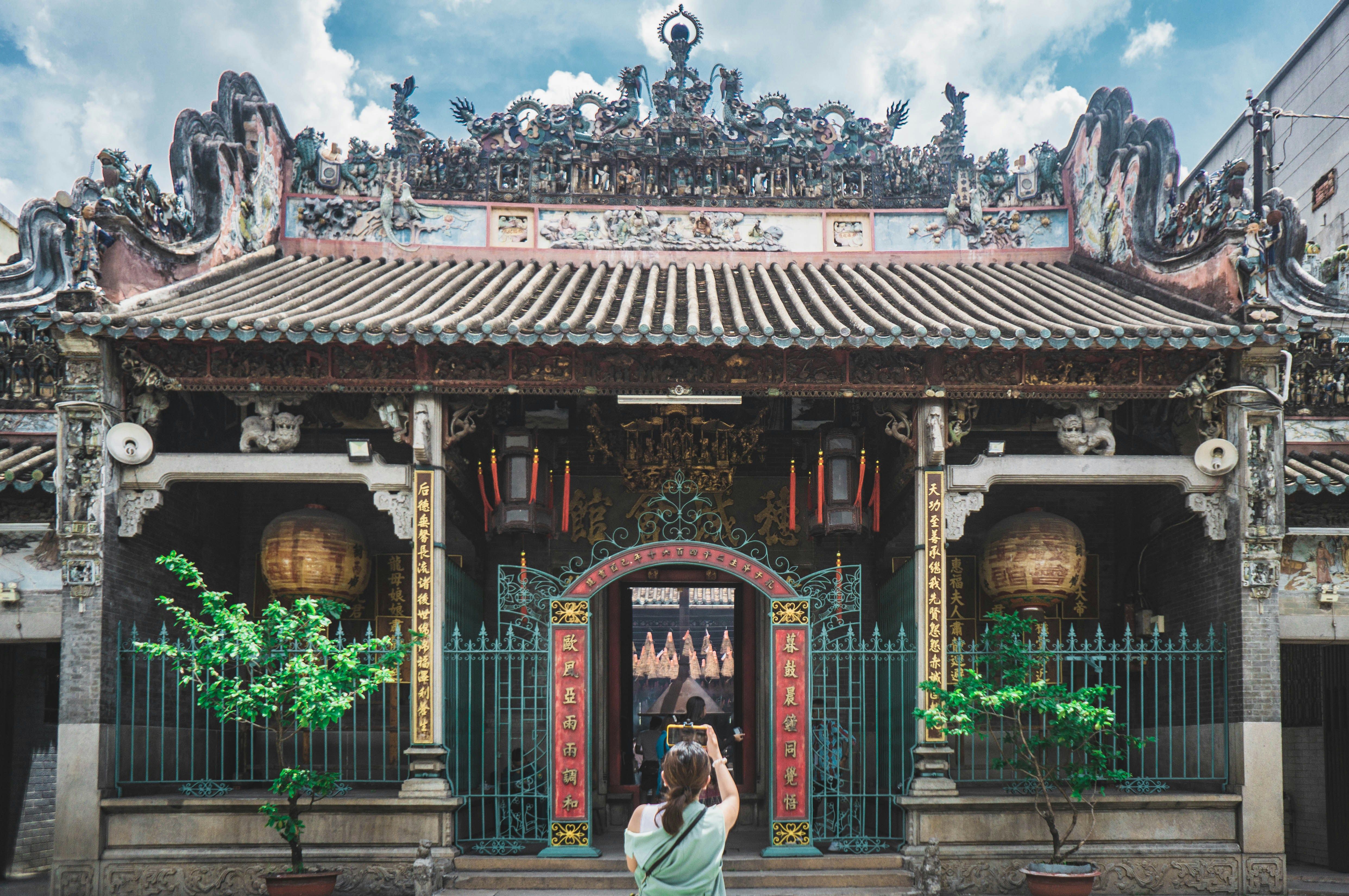 Intricate architecture of Thien Hau Temple with ornate details and two flanking potted plants.