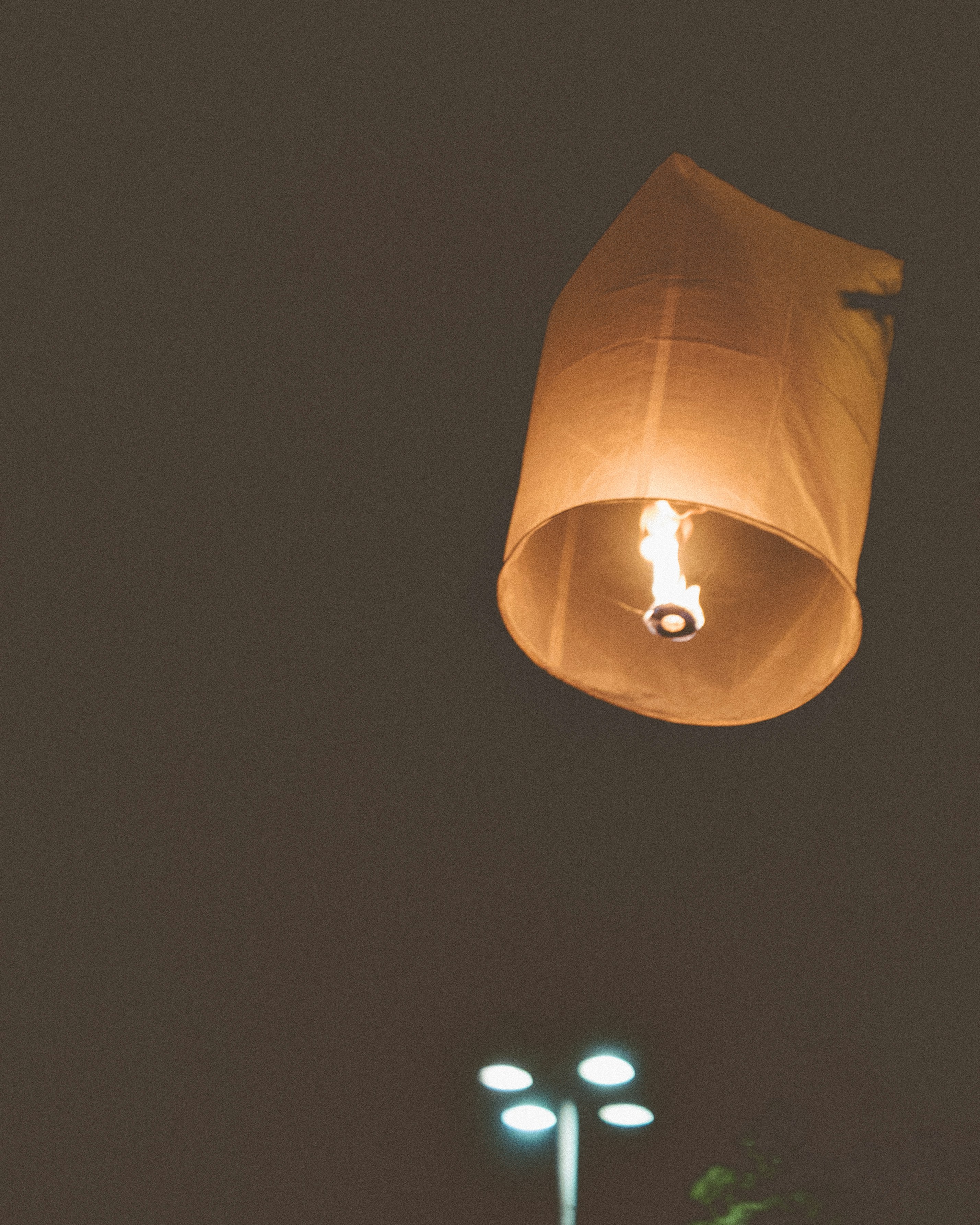 Floating lantern with a flickering flame against a dark sky, symbolizing hope and celebration.