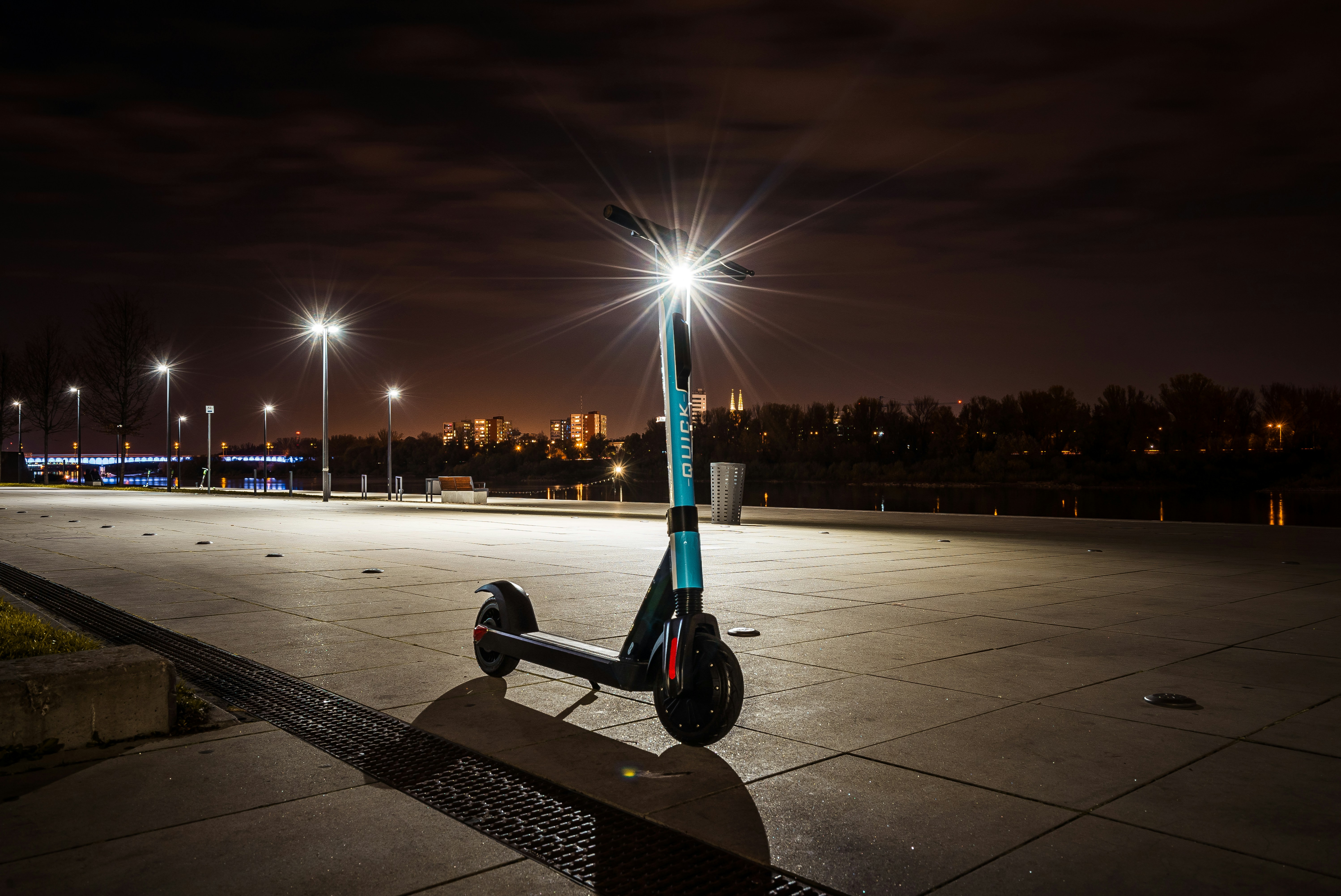Teal Kick Scooter Under City Lights: A Quiet Waterfront Night