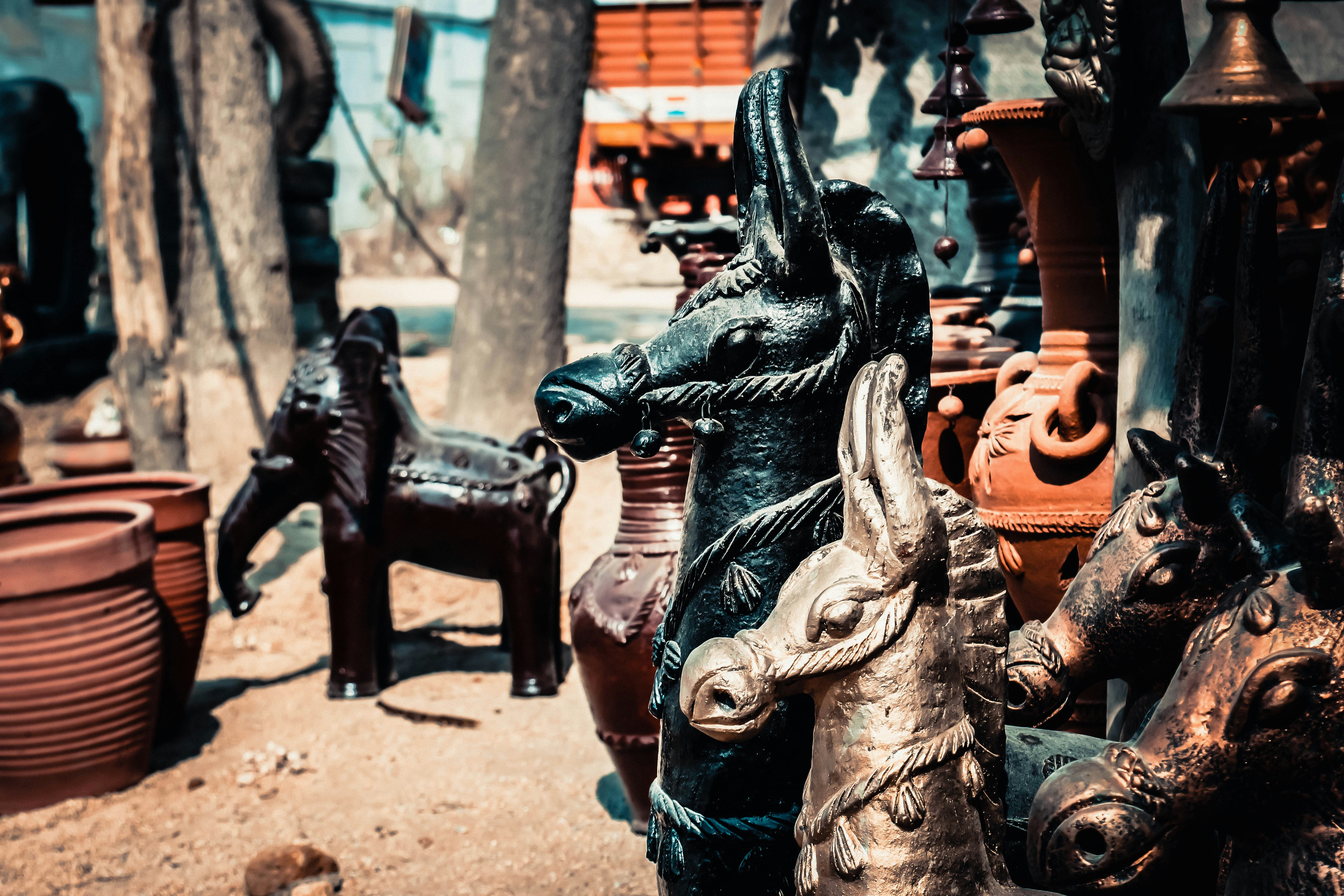 Intricately crafted clay horse figurines displayed among various pottery pieces in an artisan market.