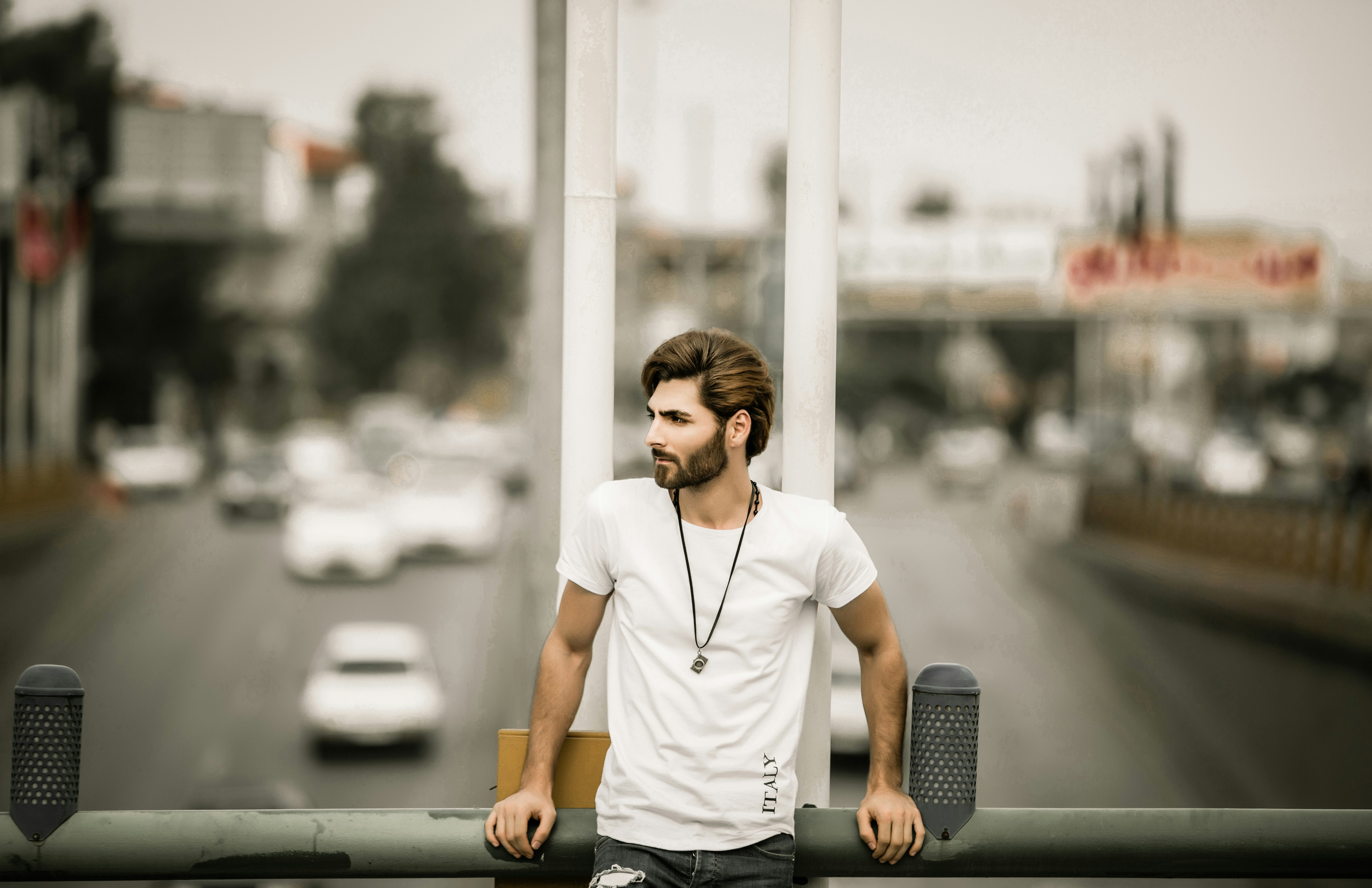 Man in white crew-neck T-shirt leaning on gray steel handrail photo ...
