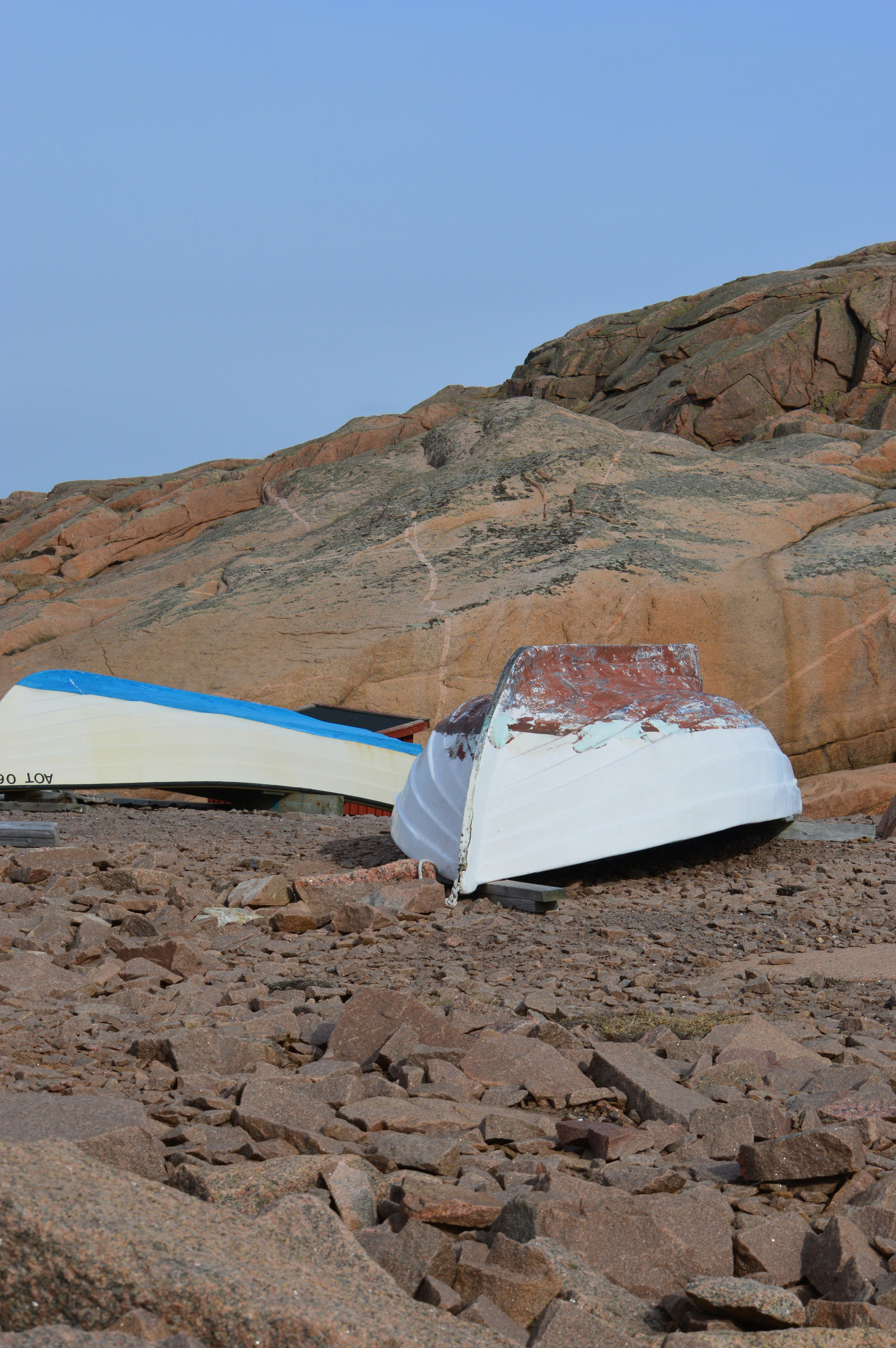 Weathered boats Rest on a Pebble Shore Beneath Rugged Granite