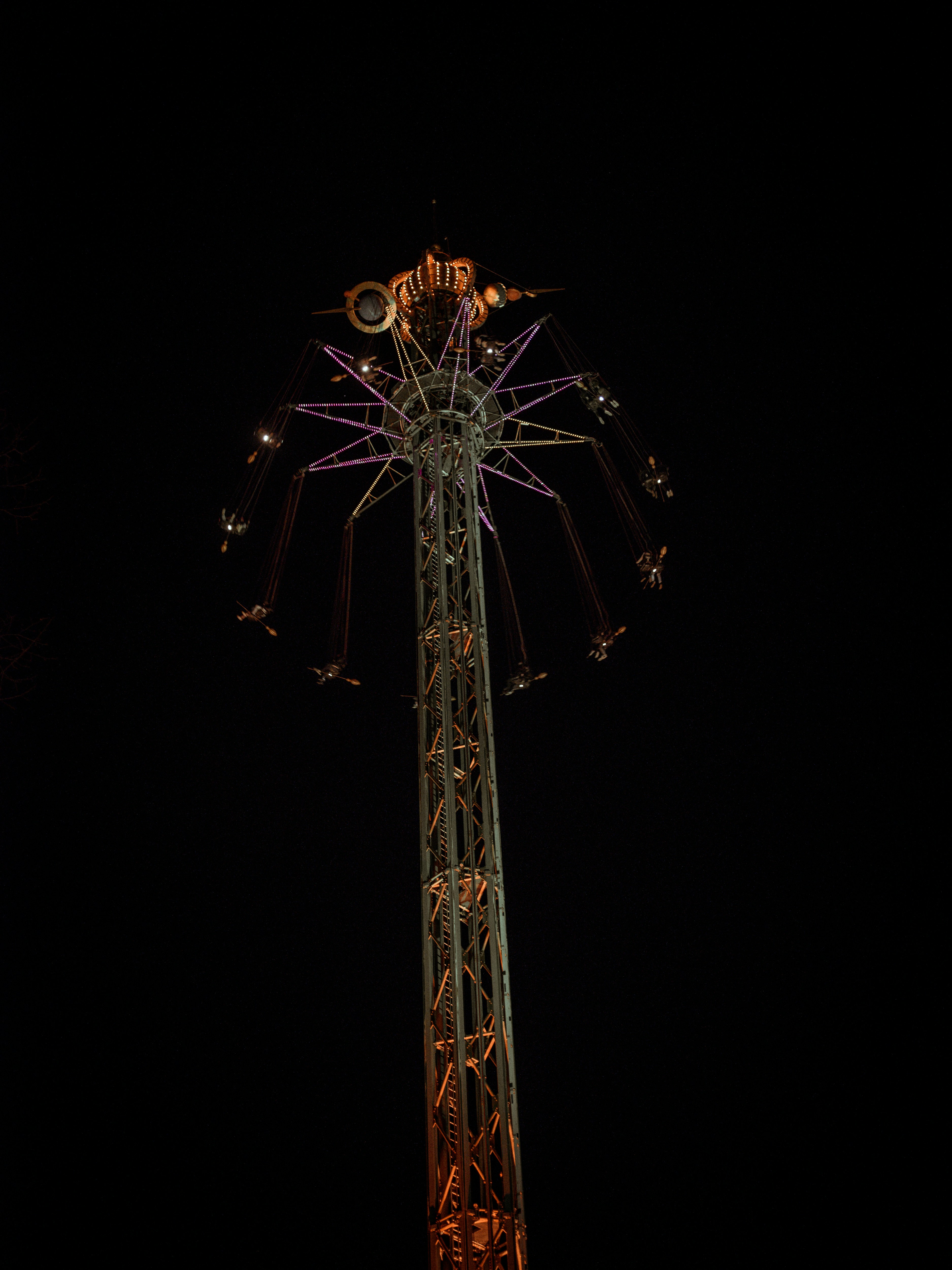 A towering amusement ride illuminated against the night sky, showcasing its intricate design and vibrant lights.