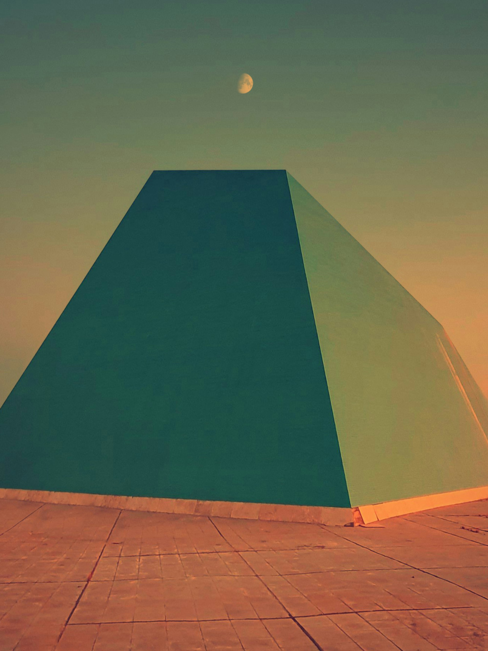 A striking pyramid structure bathed in soft twilight, with a crescent moon hovering above. The geometric lines create a sense of calm and balance.