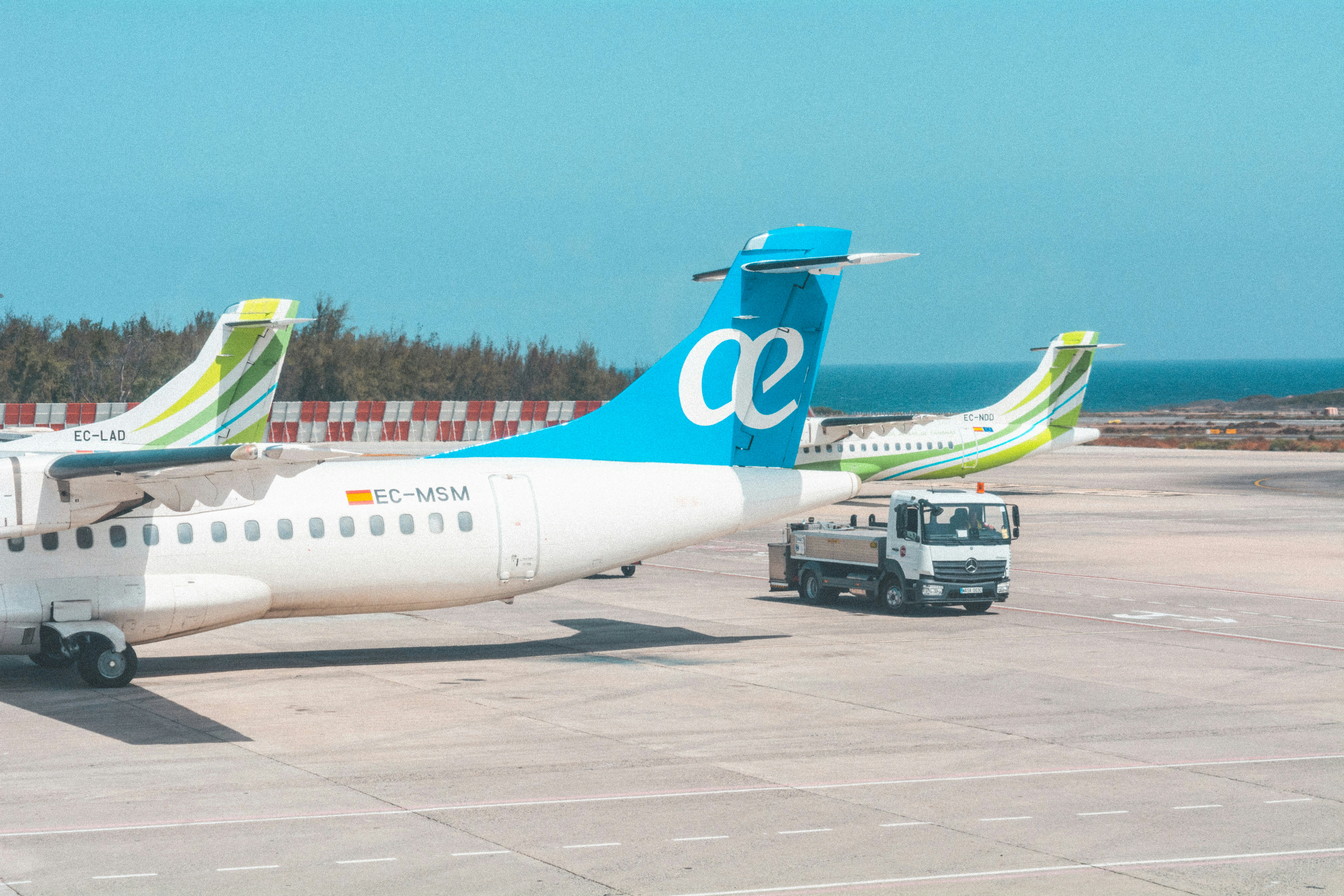 Blue-Tailed Jet on the Quiet Apron: Sunlit Row of Regional Airliners