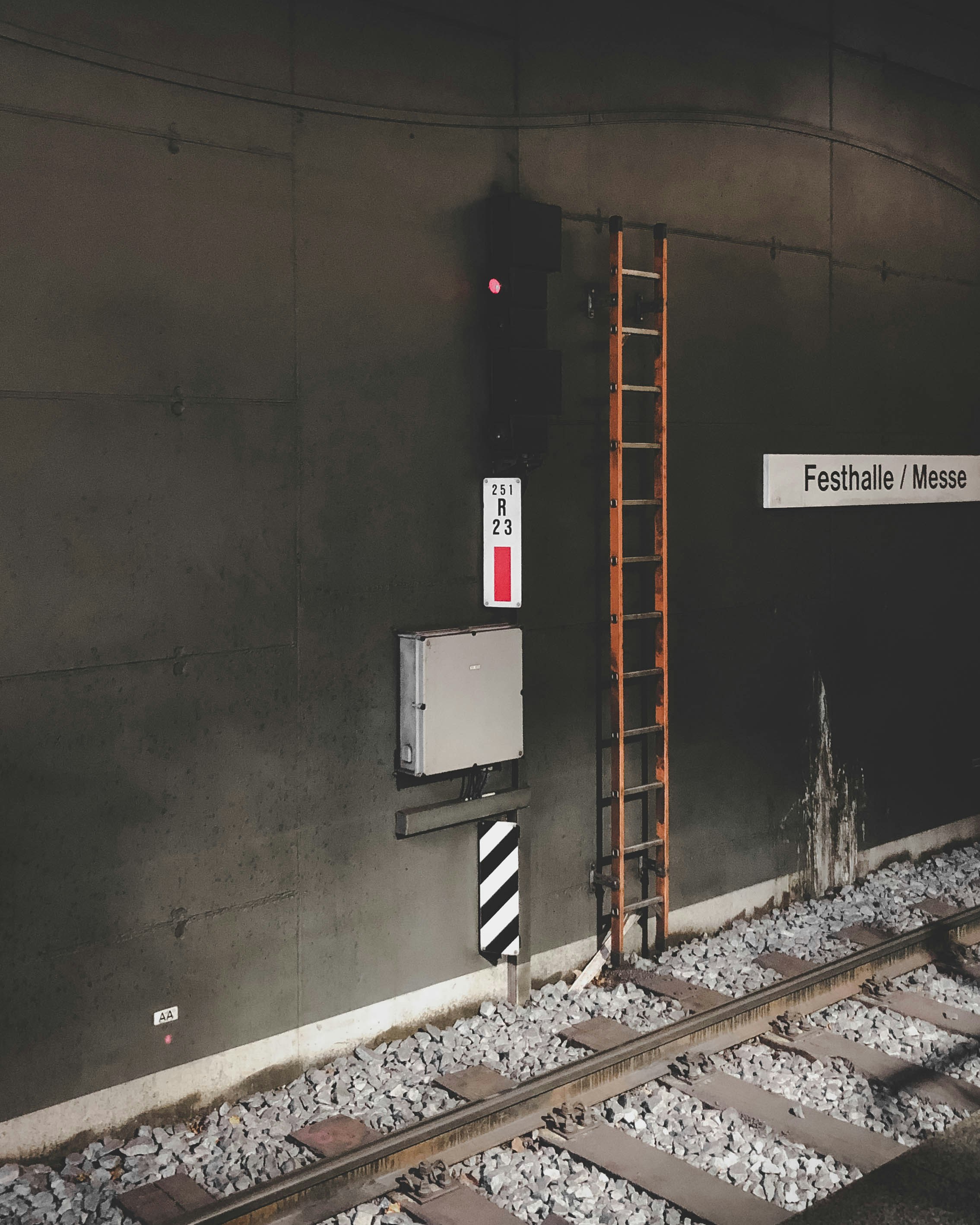 Railway signal and informational signage against a textured wall in an underground setting.