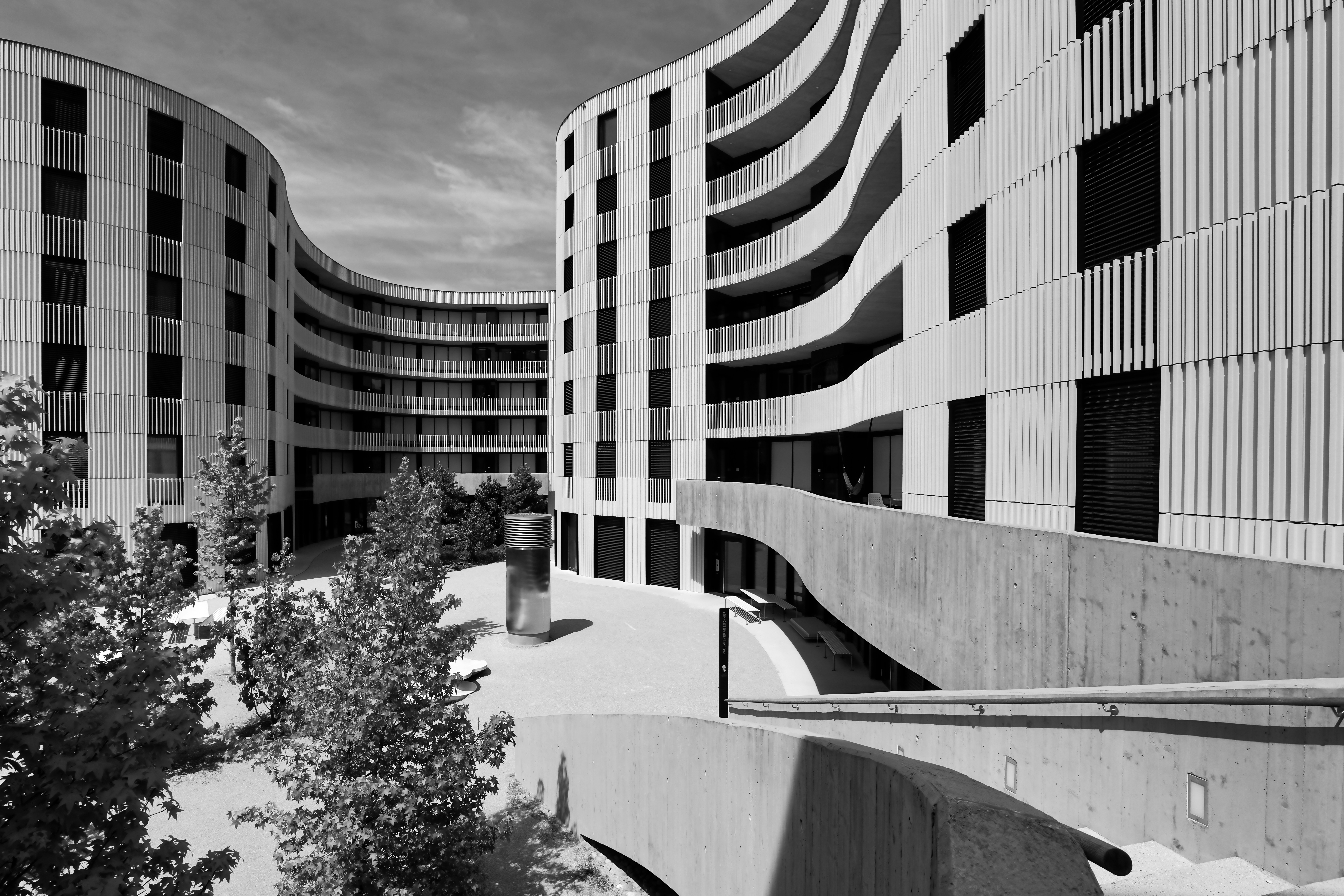 Curved modern building facades with contrasting shadows and sunlight.