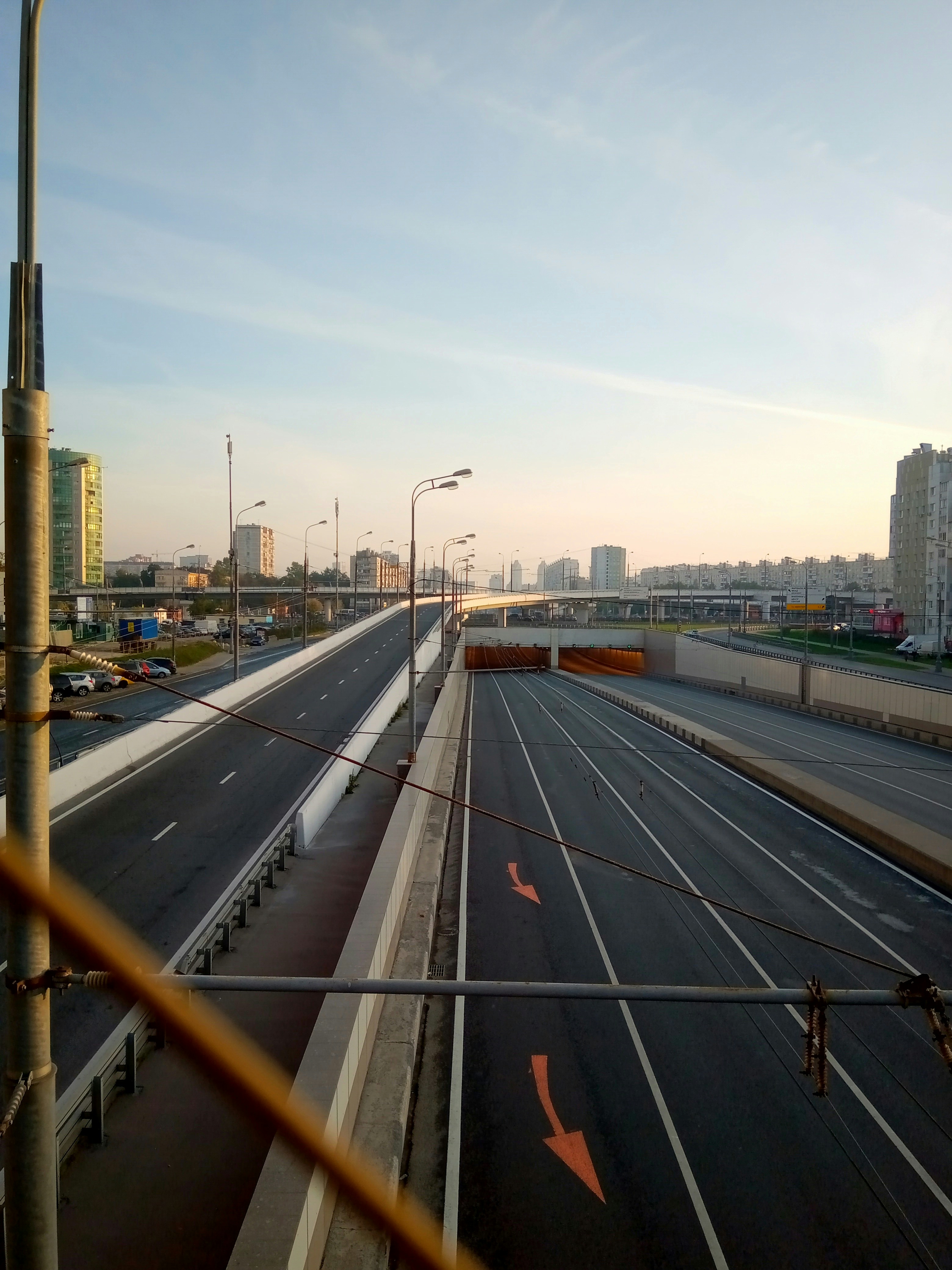 A view of a bustling urban highway with traffic and modern buildings under a clear sky. The image captures the dynamic flow of city life.