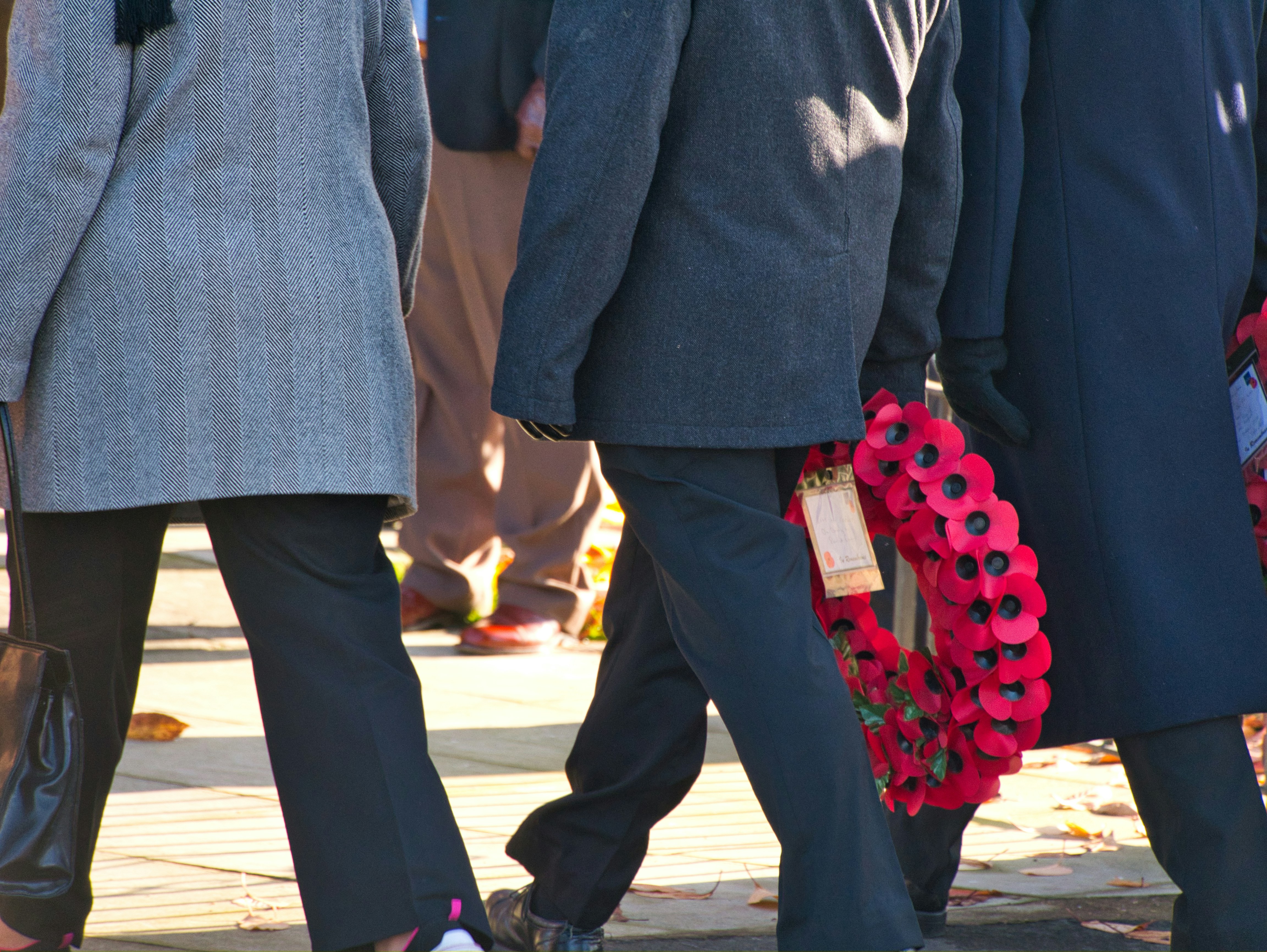 Procession of Dark Coats and a Crimson Memorial Wreath