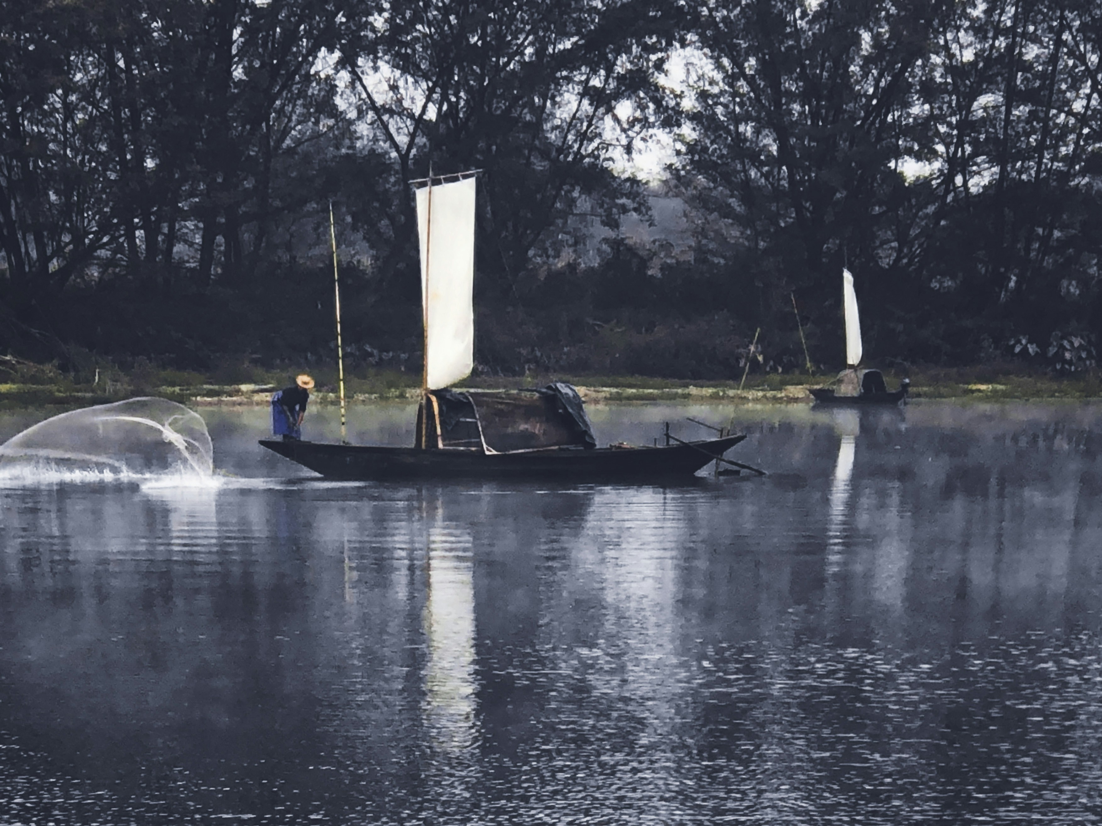 Quiet Reflections: A Sailboat Tethered on a Glassy Lake