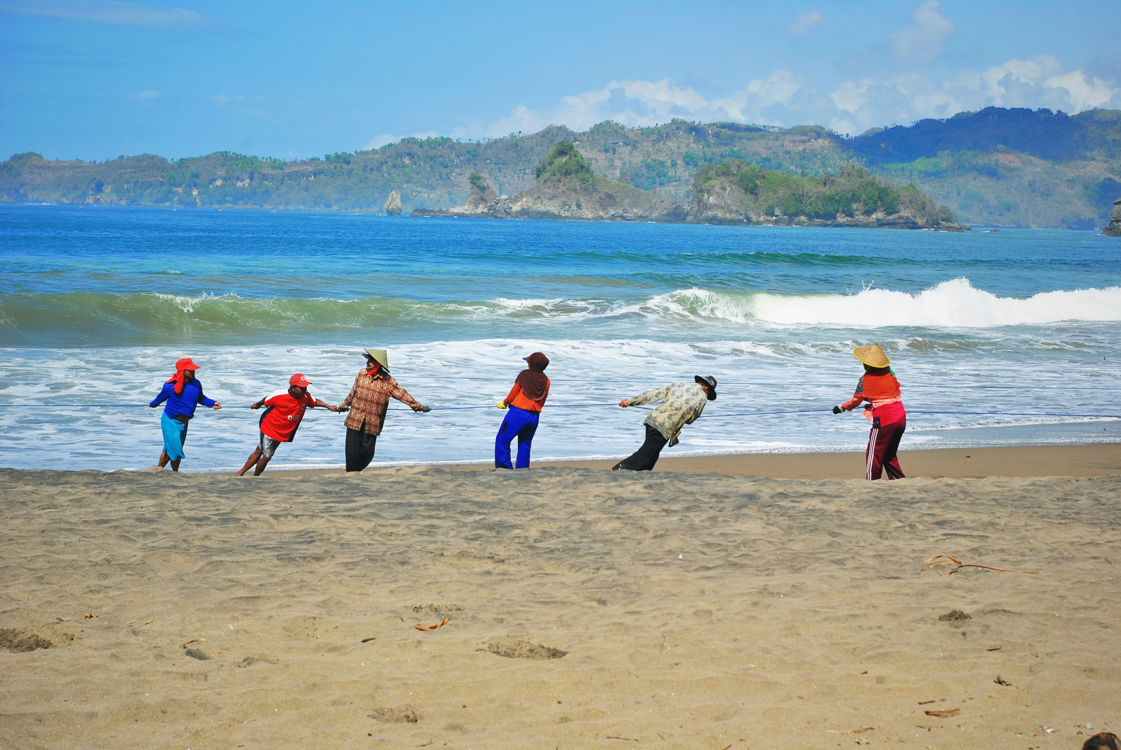 Group of individuals joyfully interacting with the waves on a sandy beach, showcasing a vibrant coastal lifestyle.