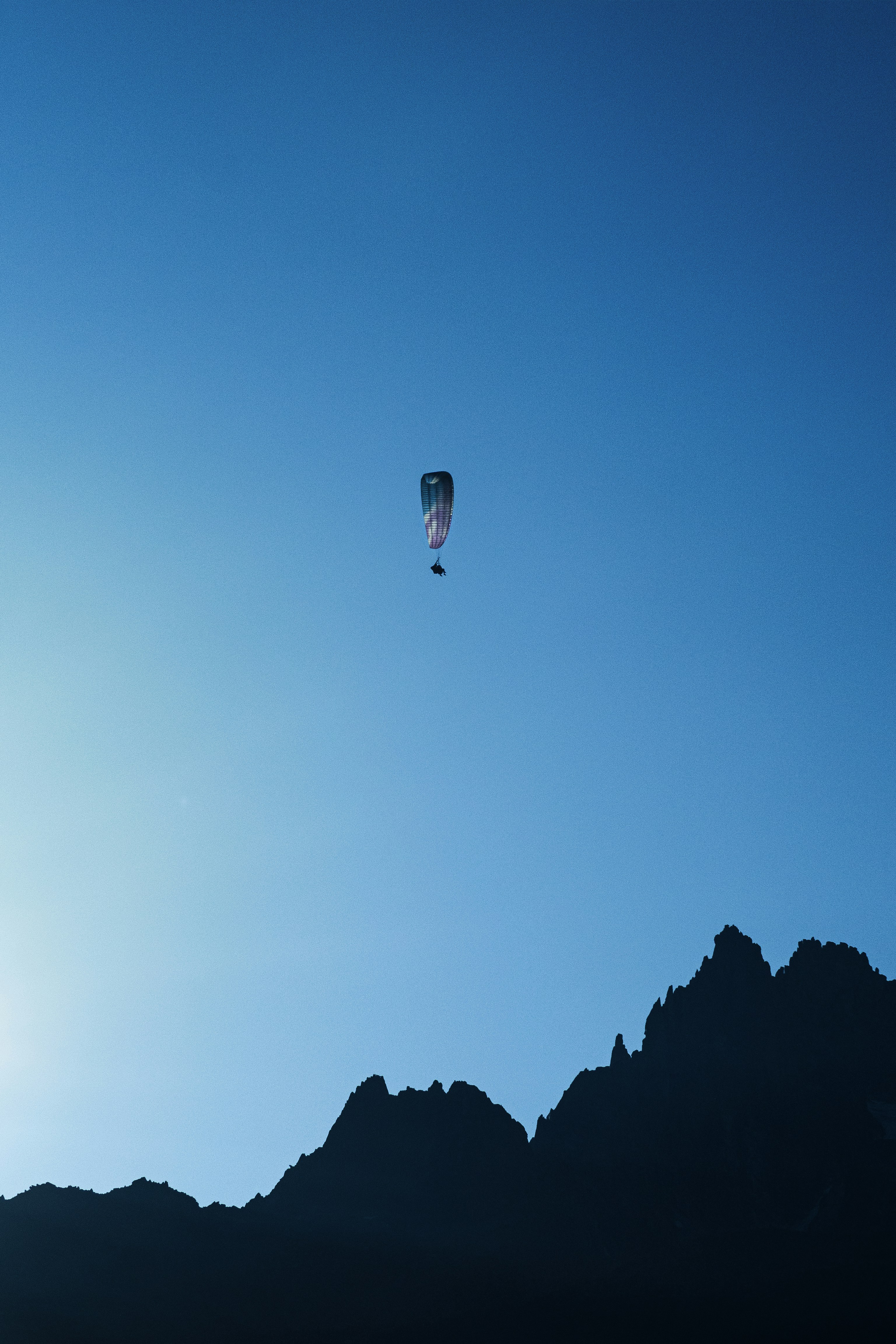 Solitary Paraglider Above Jagged Ridge at Blue Hour