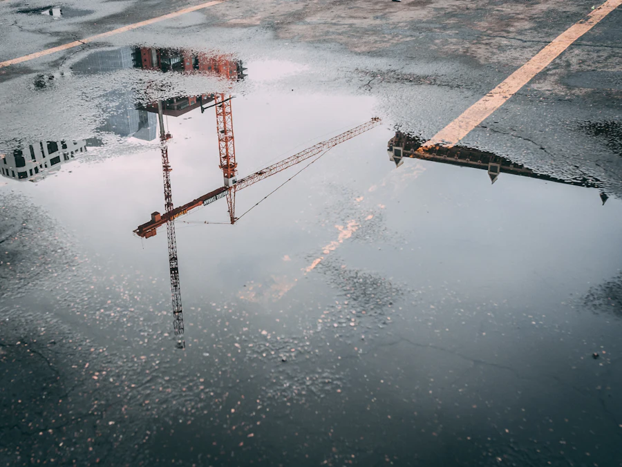 image of reflected cranes in puddle | tower crane reflecting on water