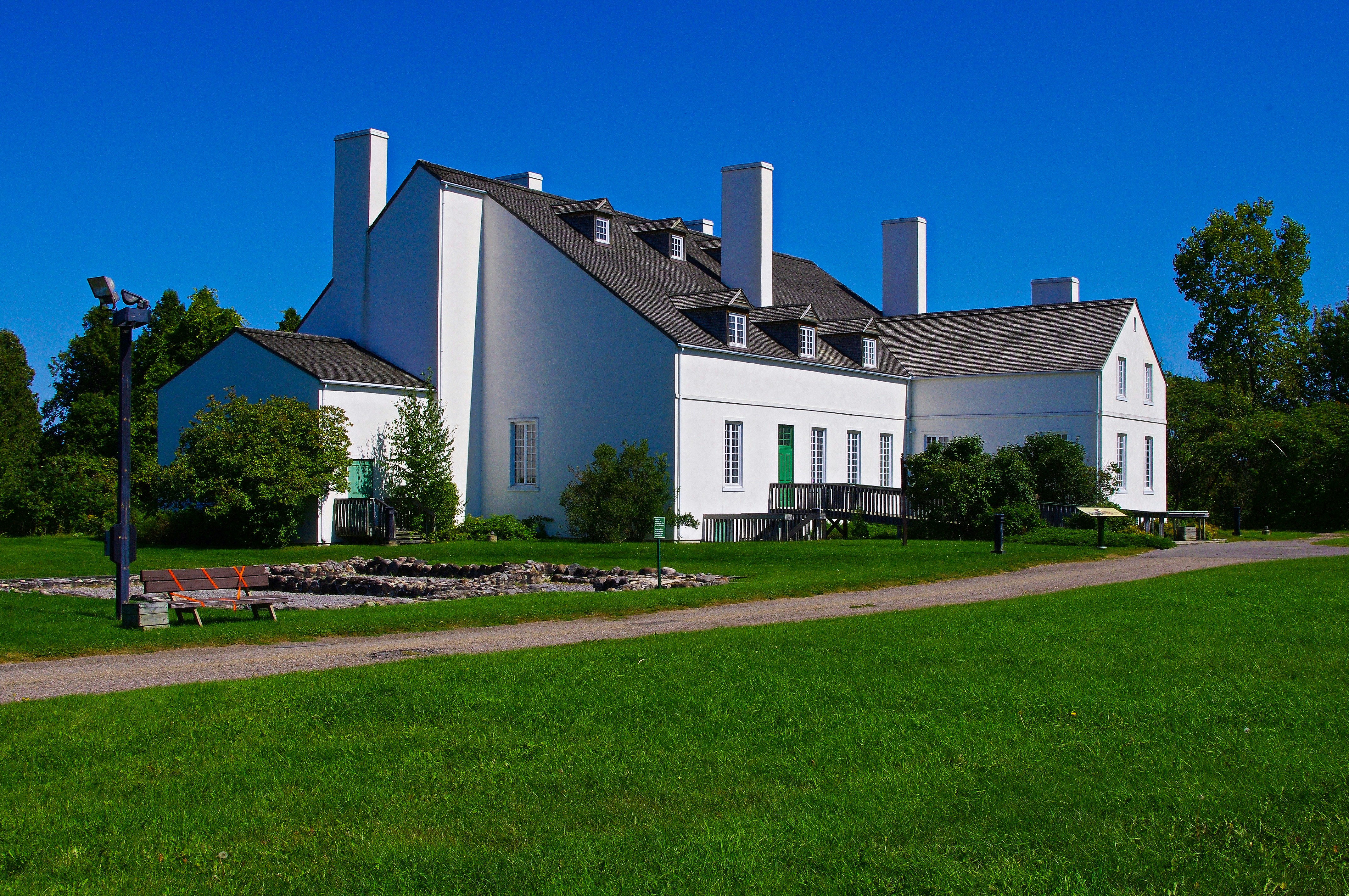 White historic buildings surrounded by lush greenery under a clear blue sky.