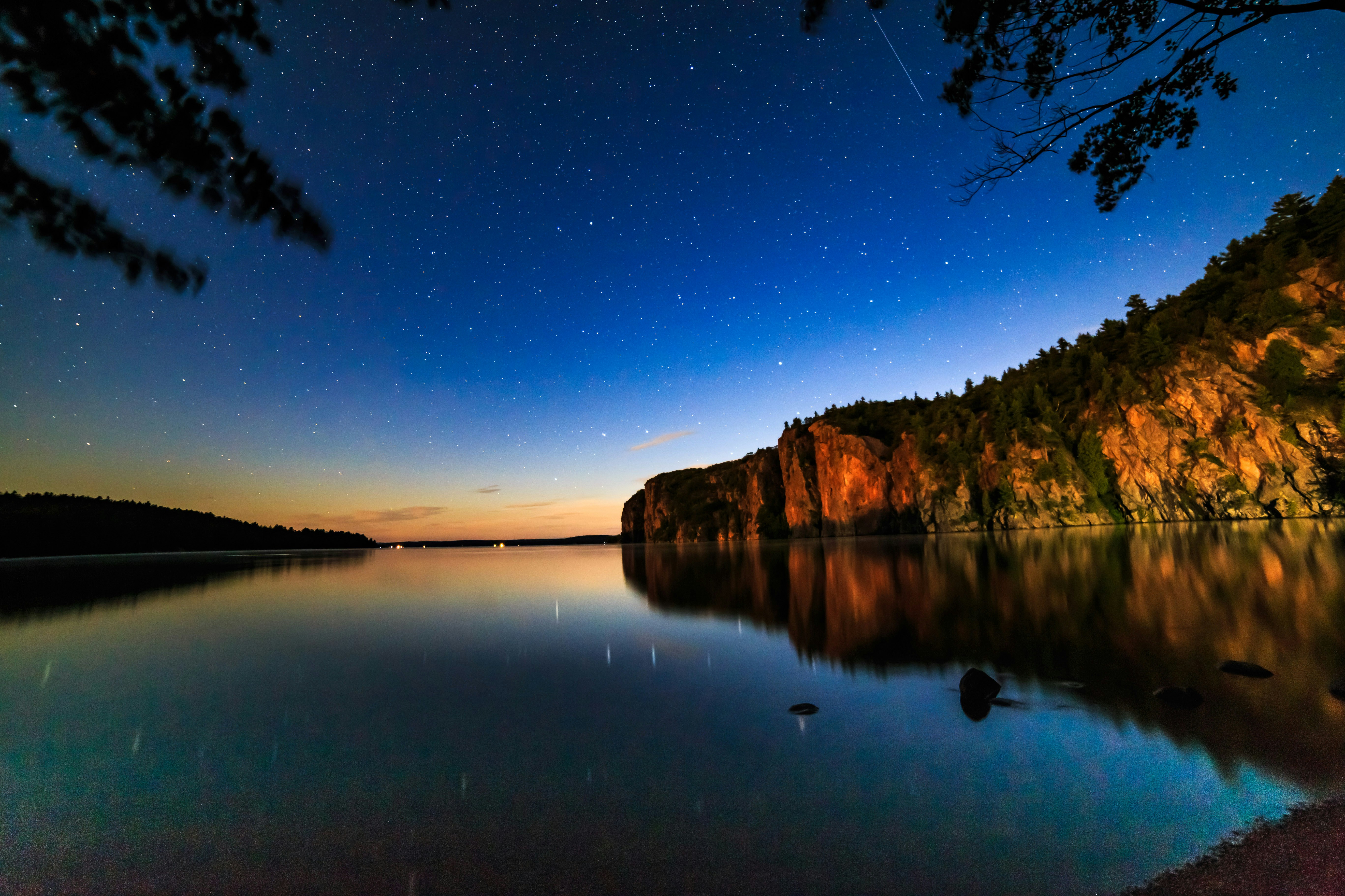 Nocturnal Quiet: Stars Mirror the Cliffside on a Glassy Lake