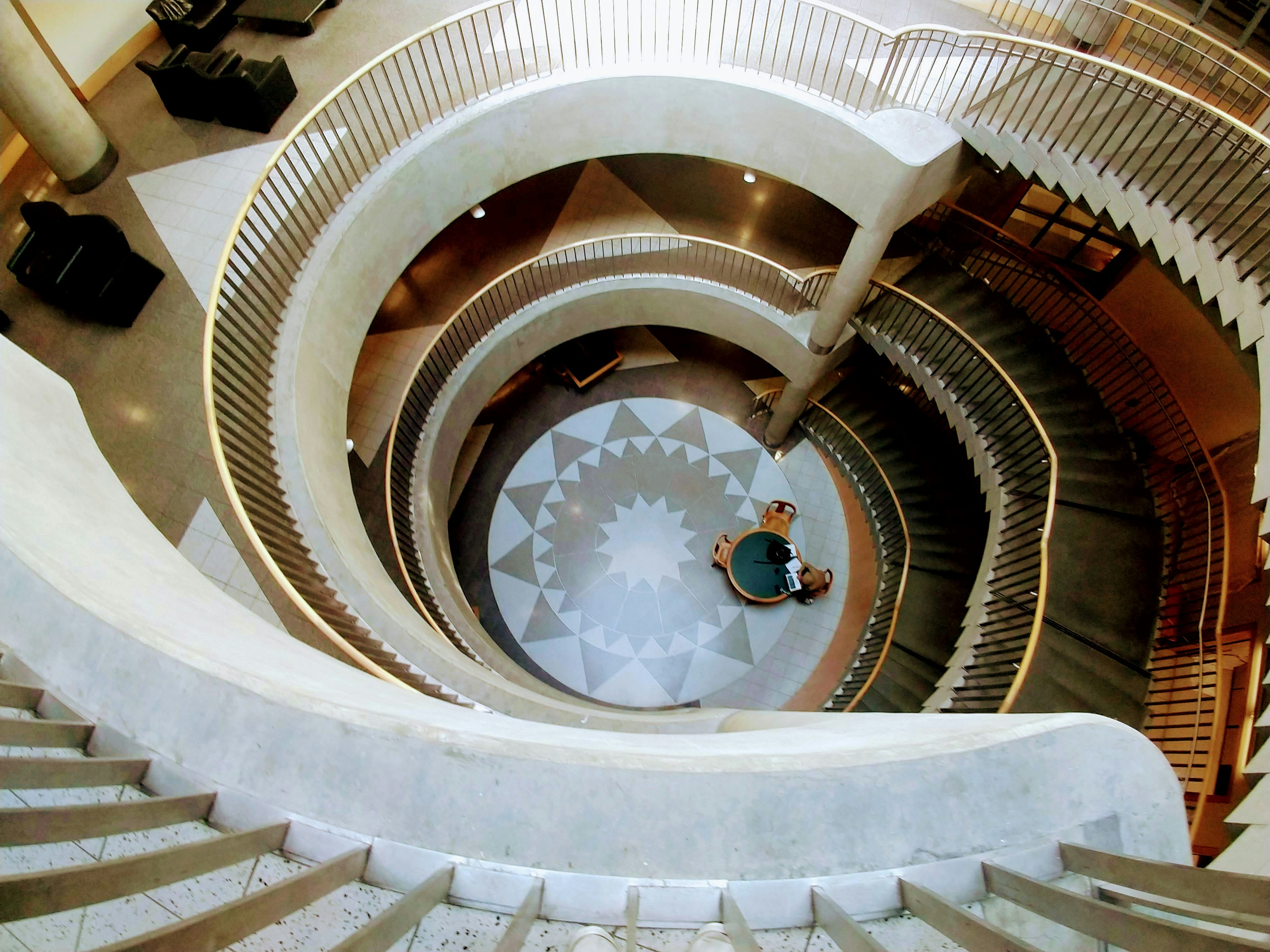Spiral staircase with a geometric floor pattern at the base viewed from above.