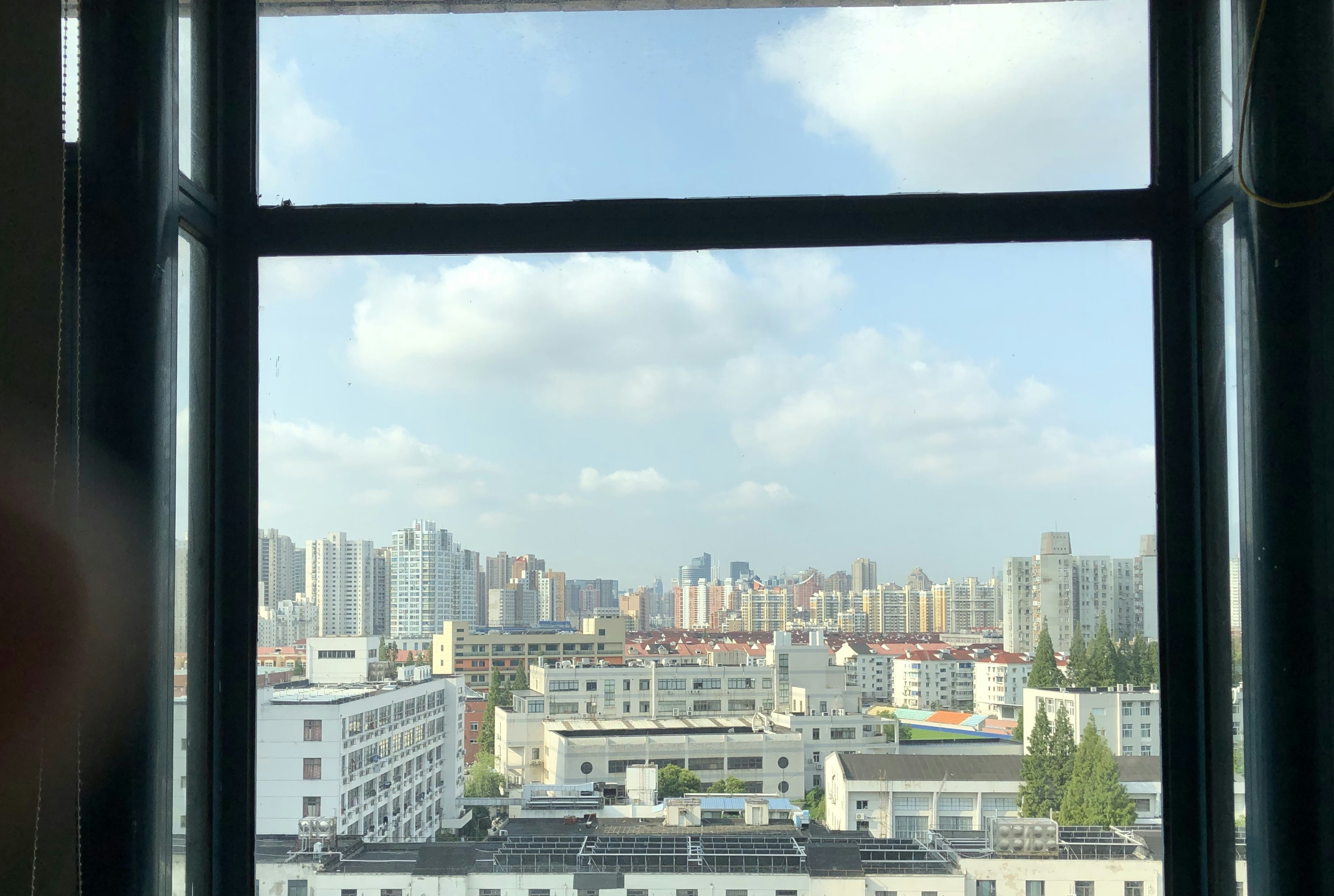 Cityscape view framed by a window, showcasing a blend of modern architecture and urban life.