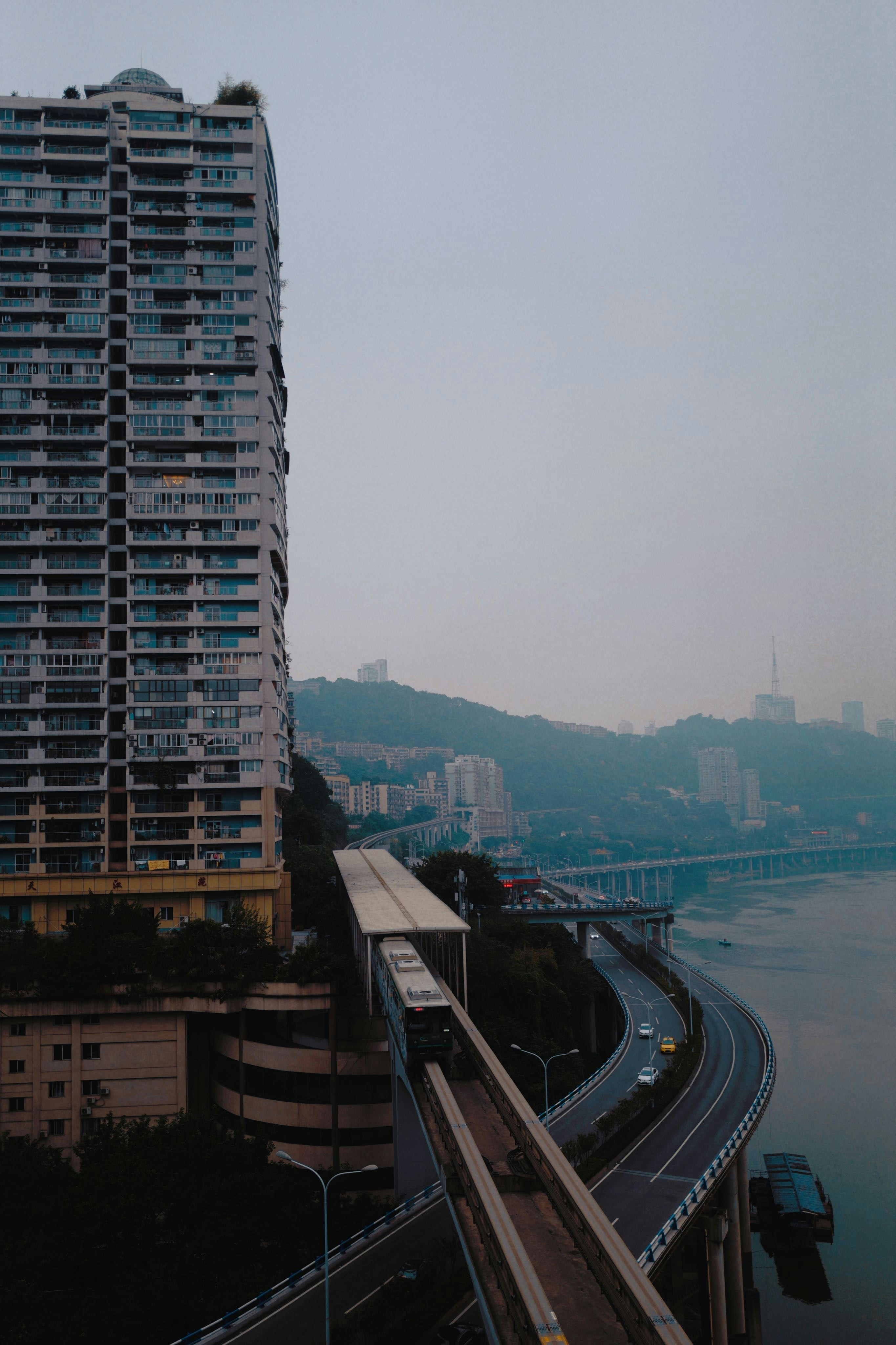 Vertical Giants Over a Winding Riverfront: A Monorail Traces the City Edge