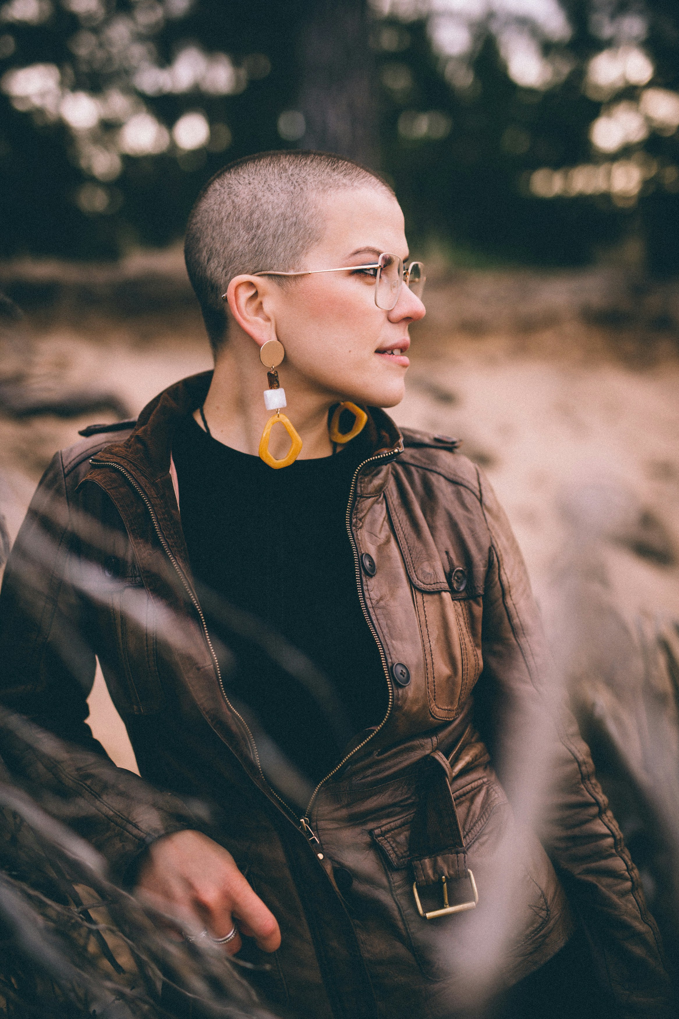 Stylish and good looking girl with short hair and glasses looking to one side in outdoor photoshoot, autumn mood, warm colours in Gauja, Latvia.