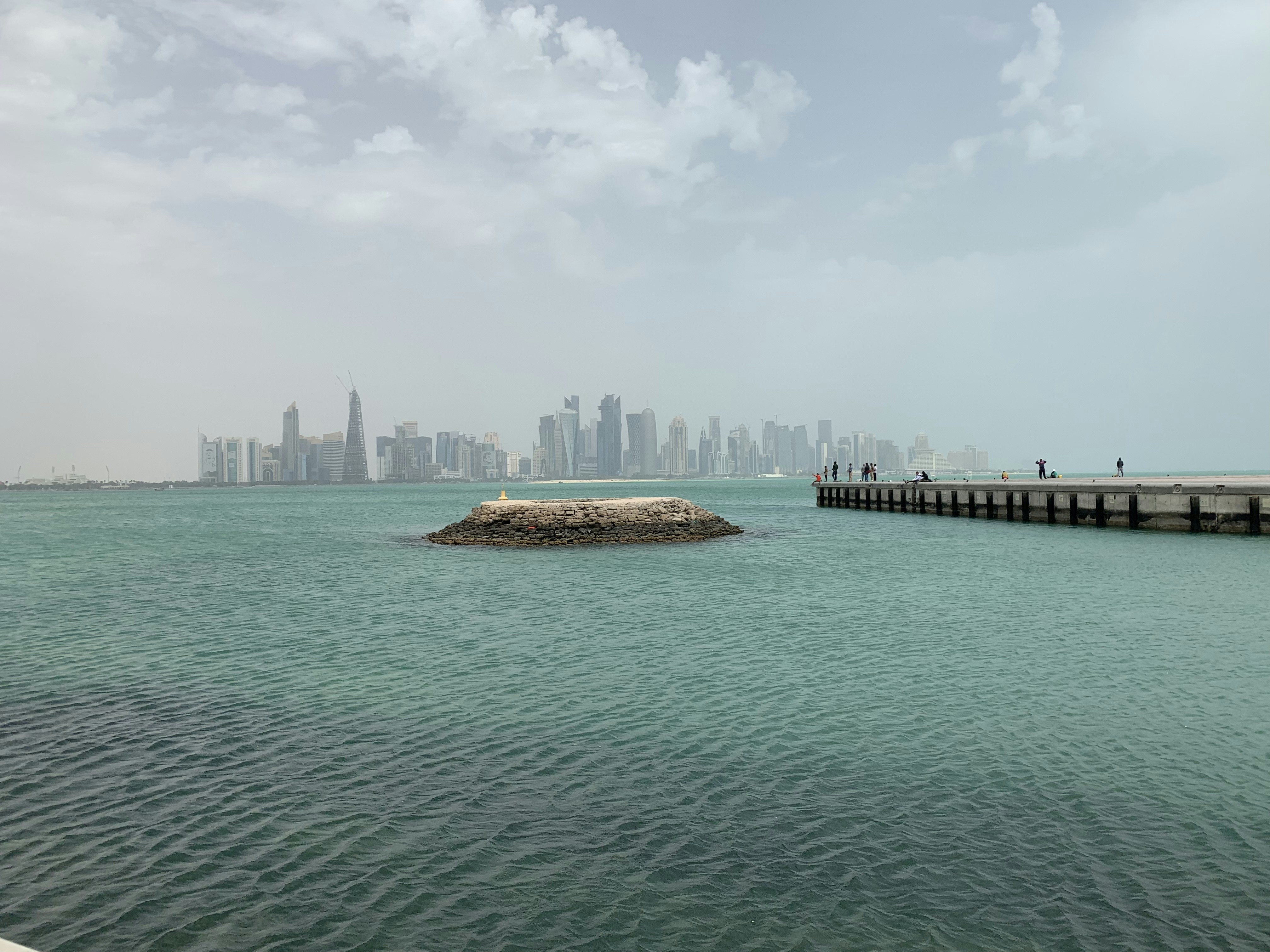 Gray beach dock viewing city with high-rise buildings under white and ...