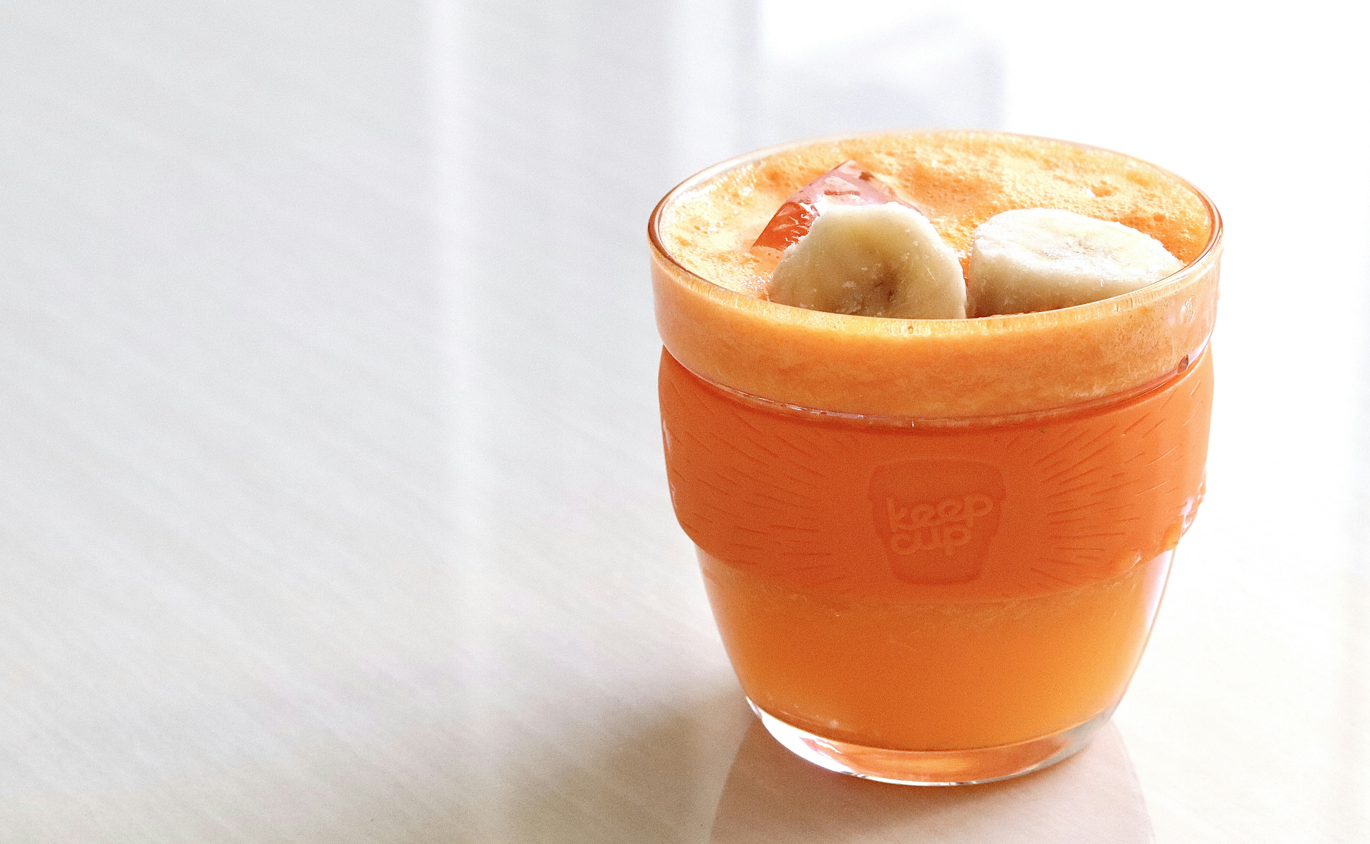 a glass of orange juice with bananas in it