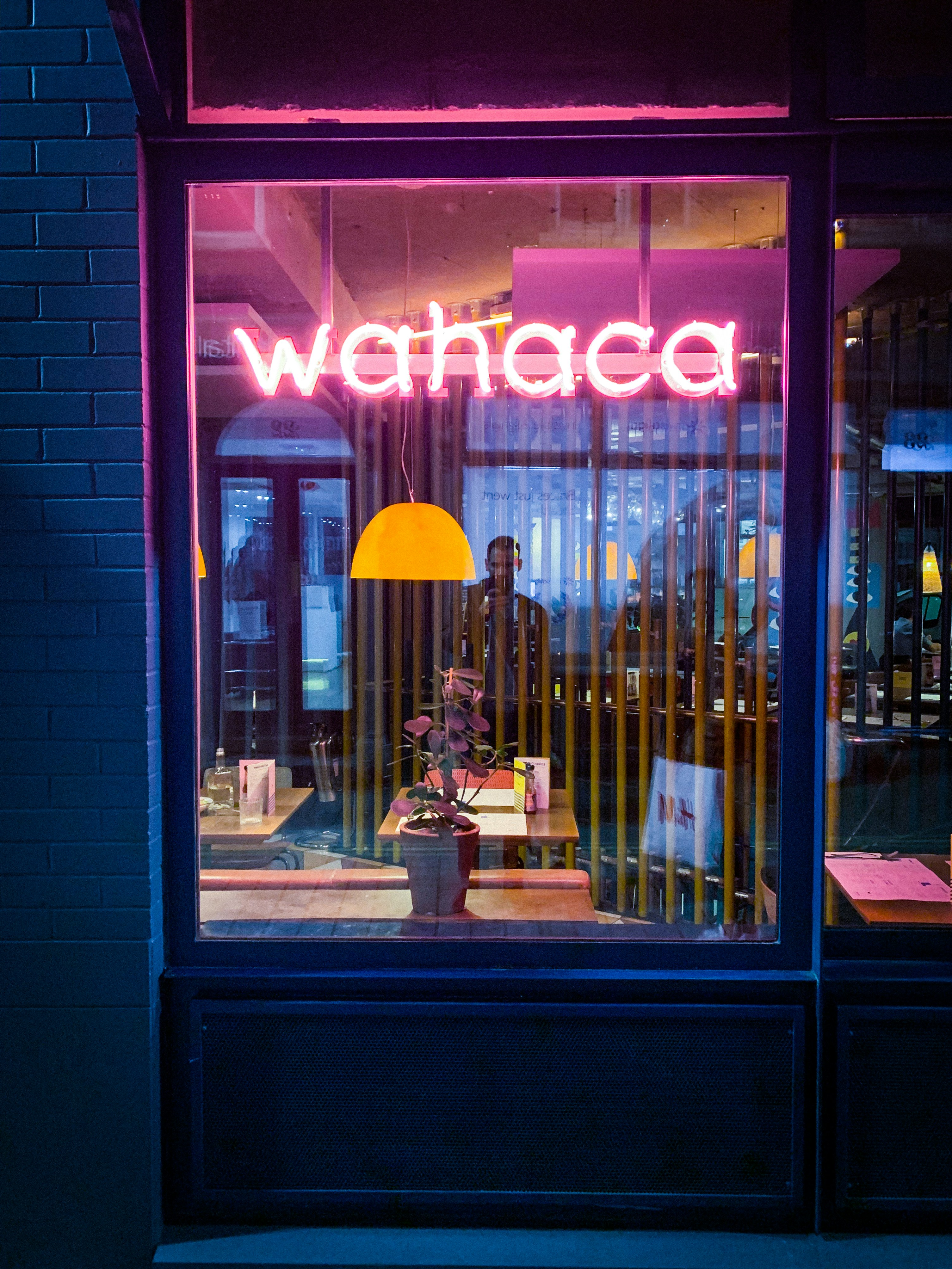Neon Wedge: A Night Shot of a Café Window Framed by Blue Brick