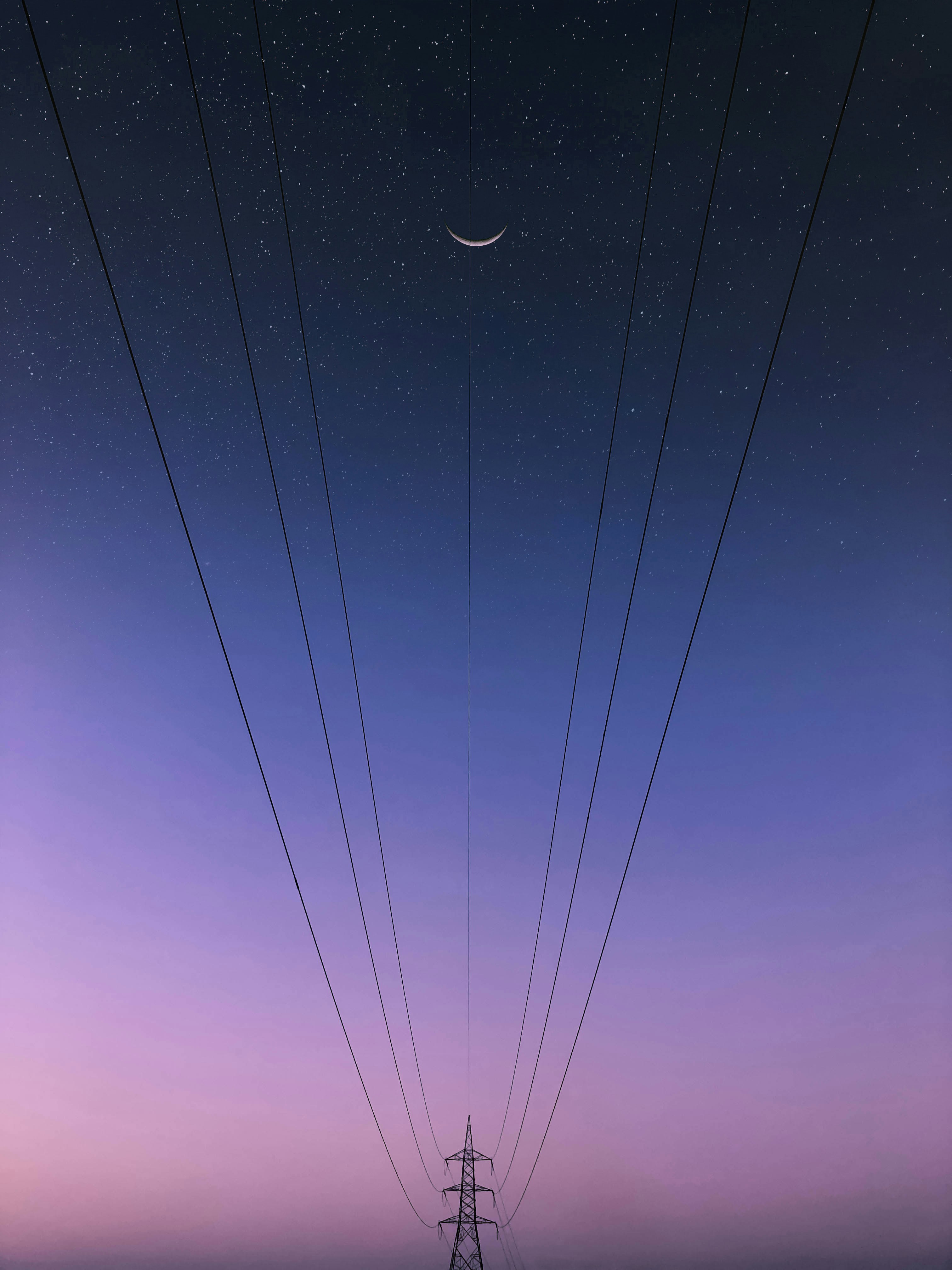 Power lines stretch towards a crescent moon in a starry twilight sky, creating a serene juxtaposition of nature and infrastructure.
