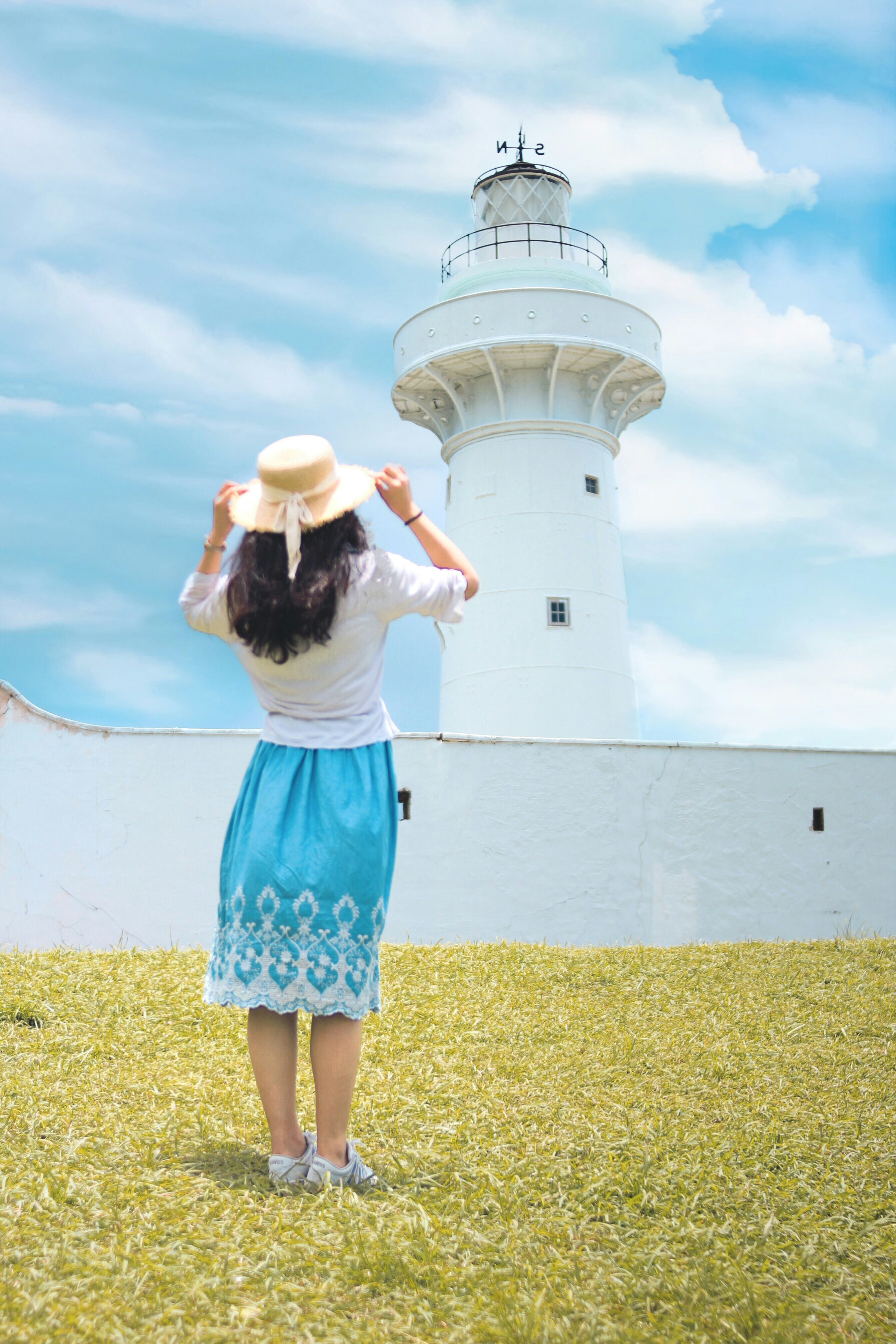 Lighthouse Gaze: A Woman in a Turquoise Lace Skirt with a Straw Hat